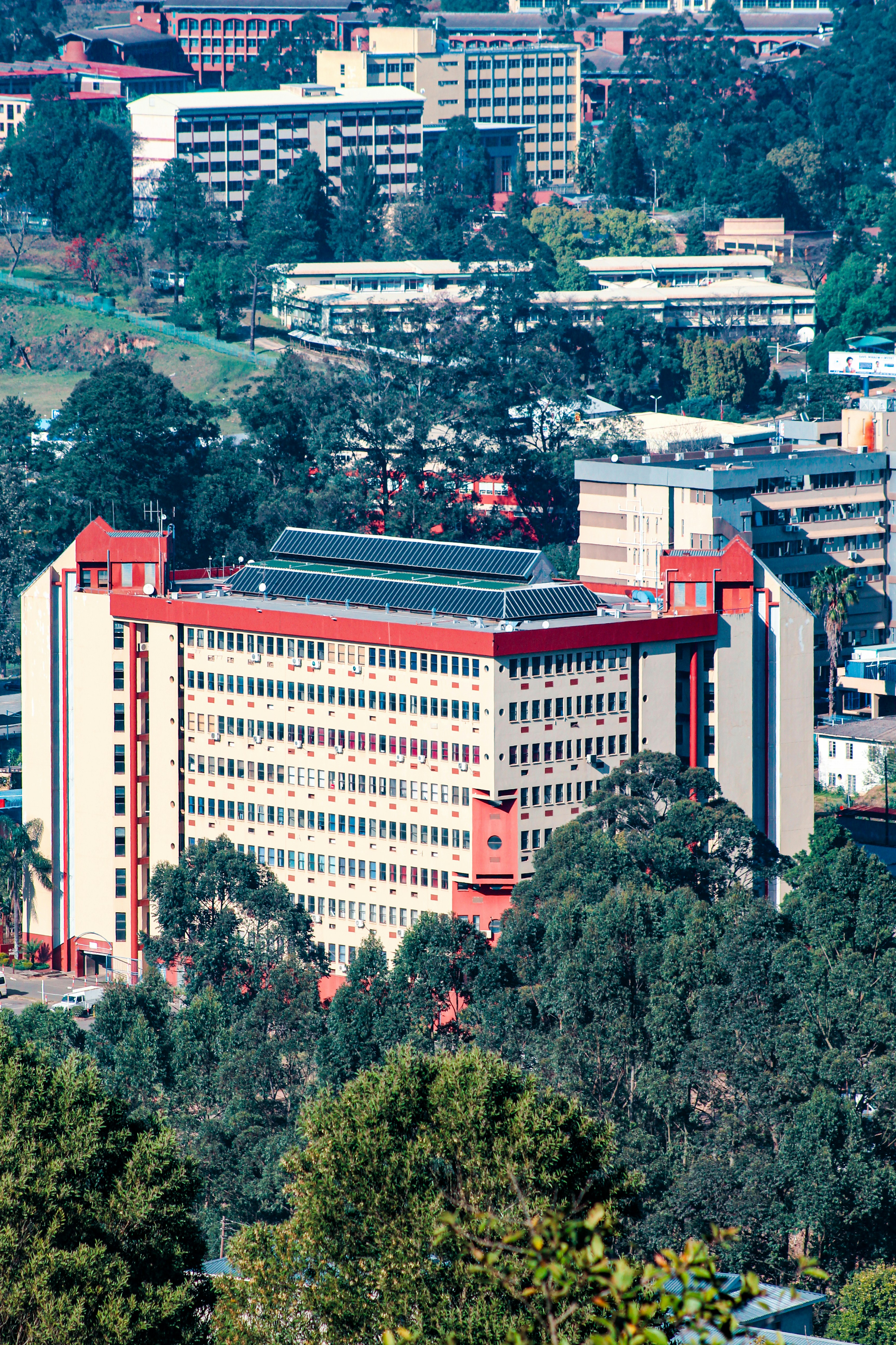 Modern building surrounded by green trees and cityscape.