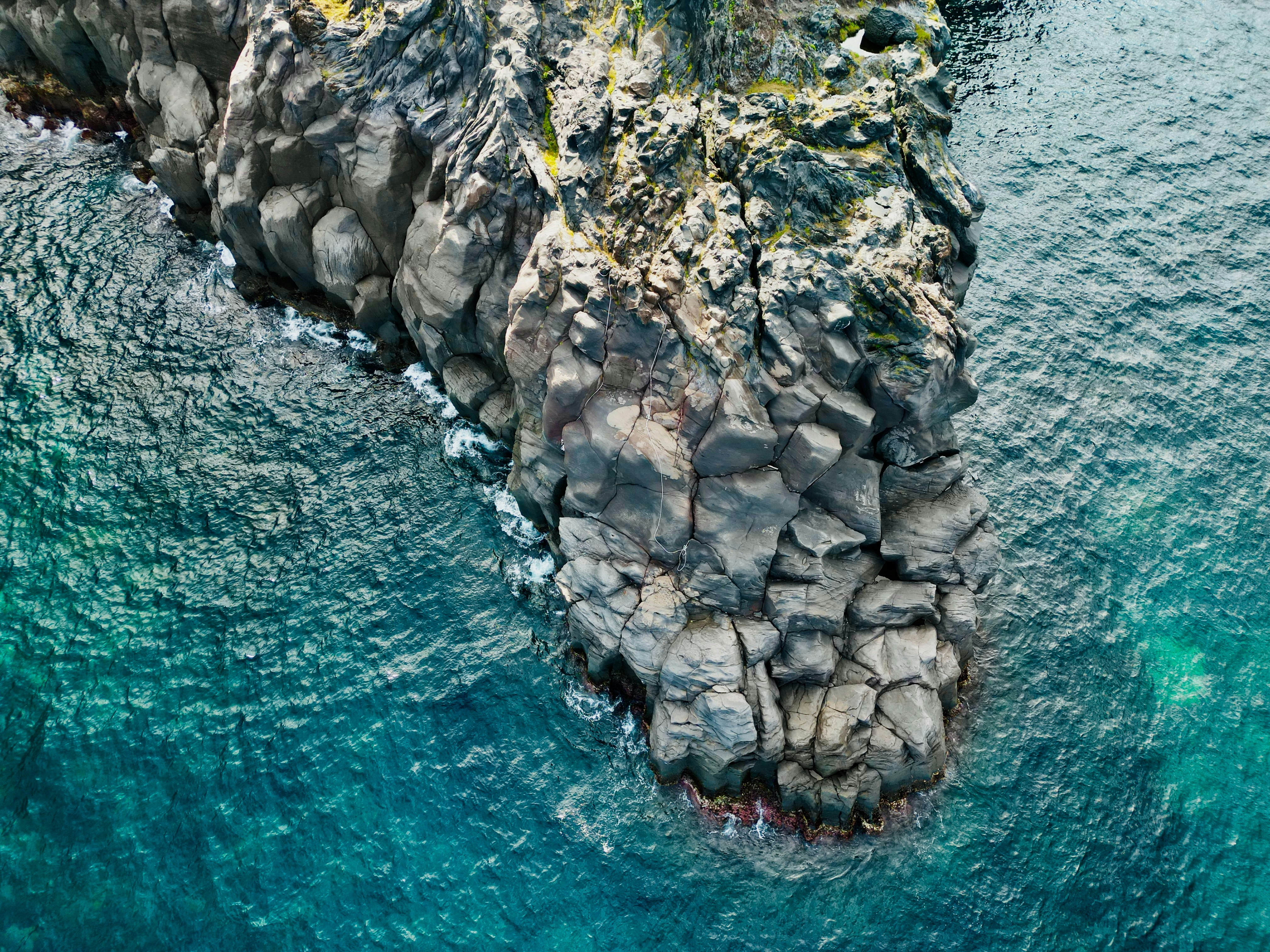 ito japan | Jagged rock formation emerges from clear blue ocean water