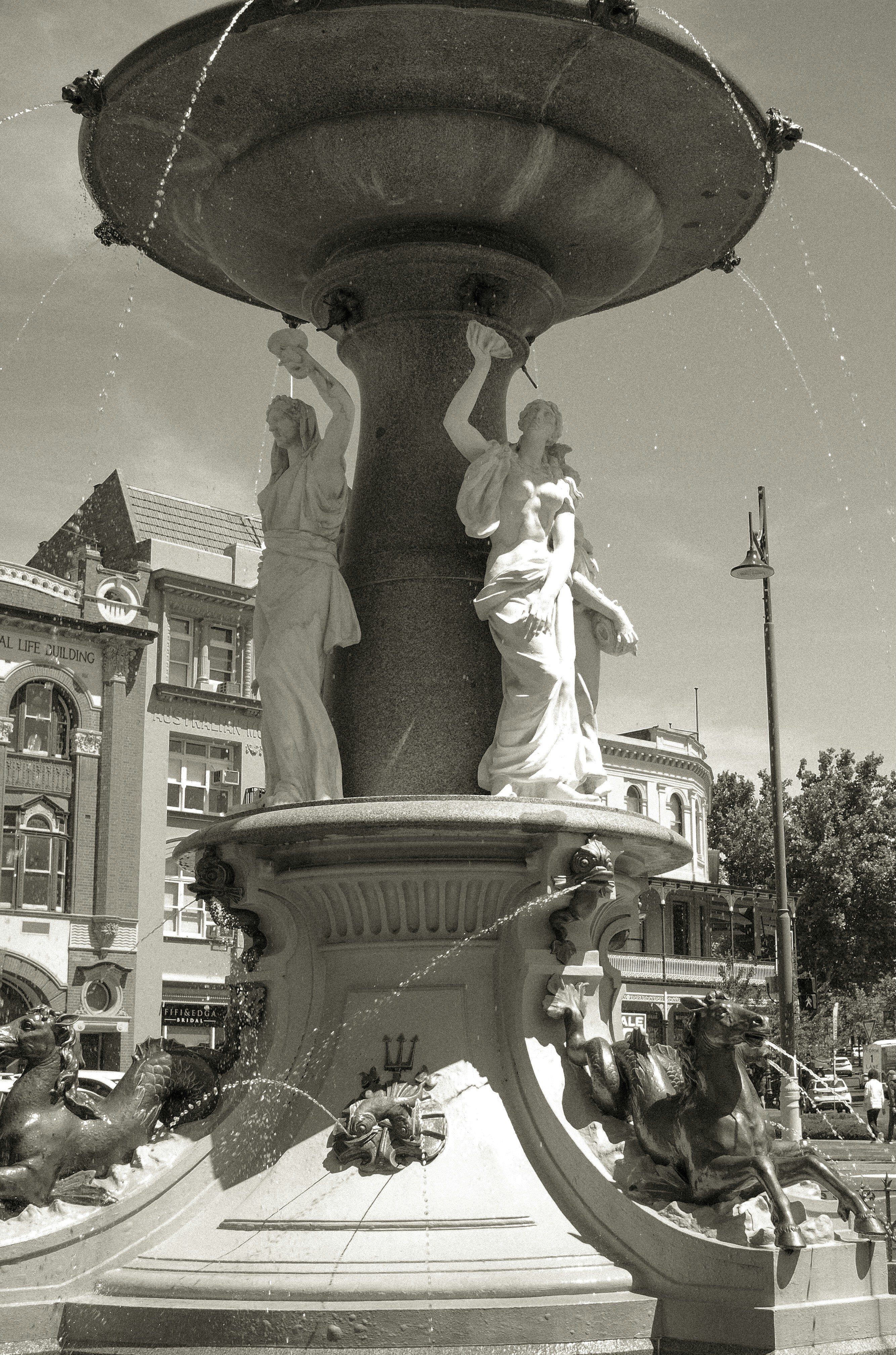 Ornate stone fountain with statues in sepia tone