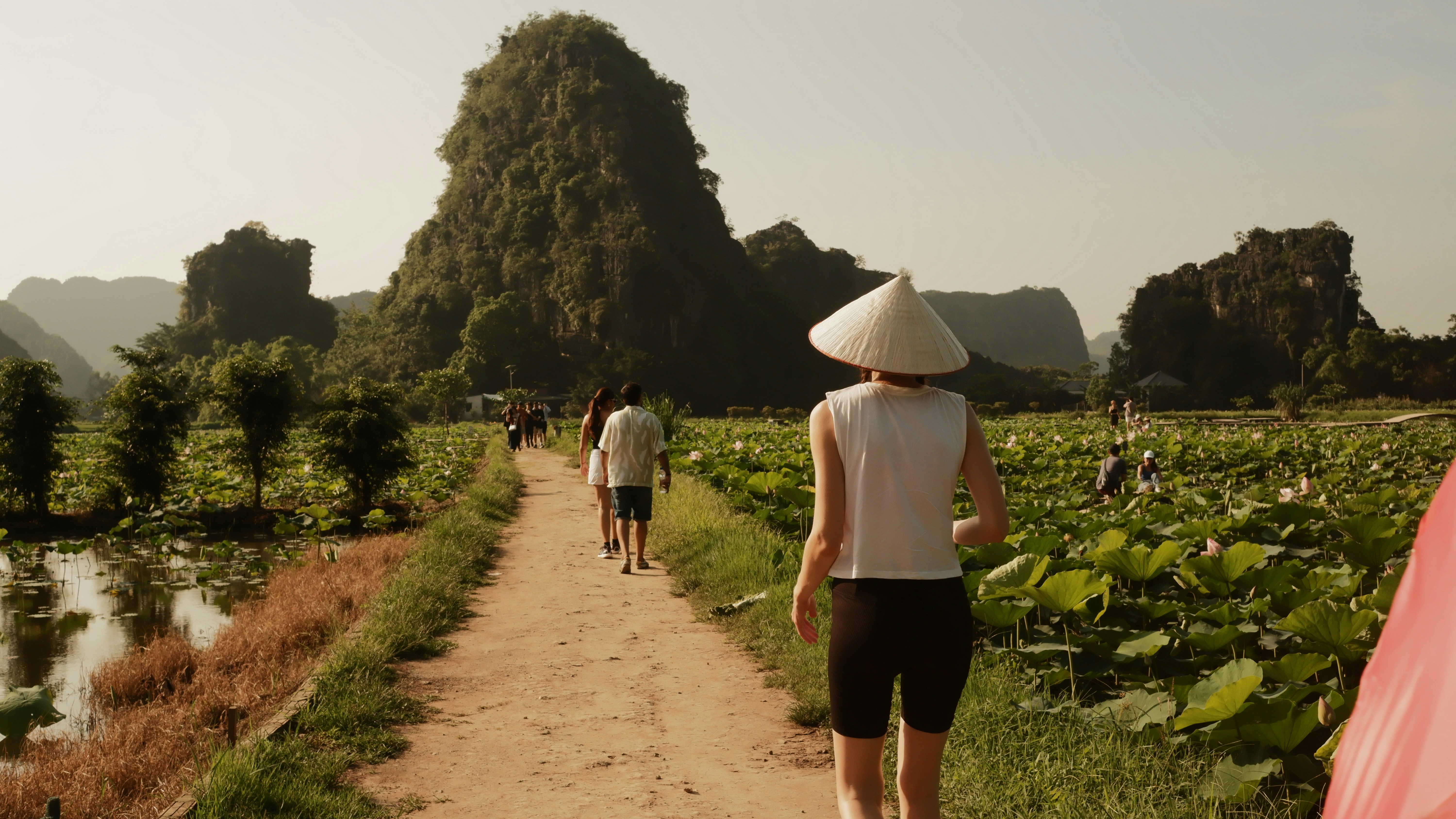 Wanderer on a sunlit path toward distant karst towers