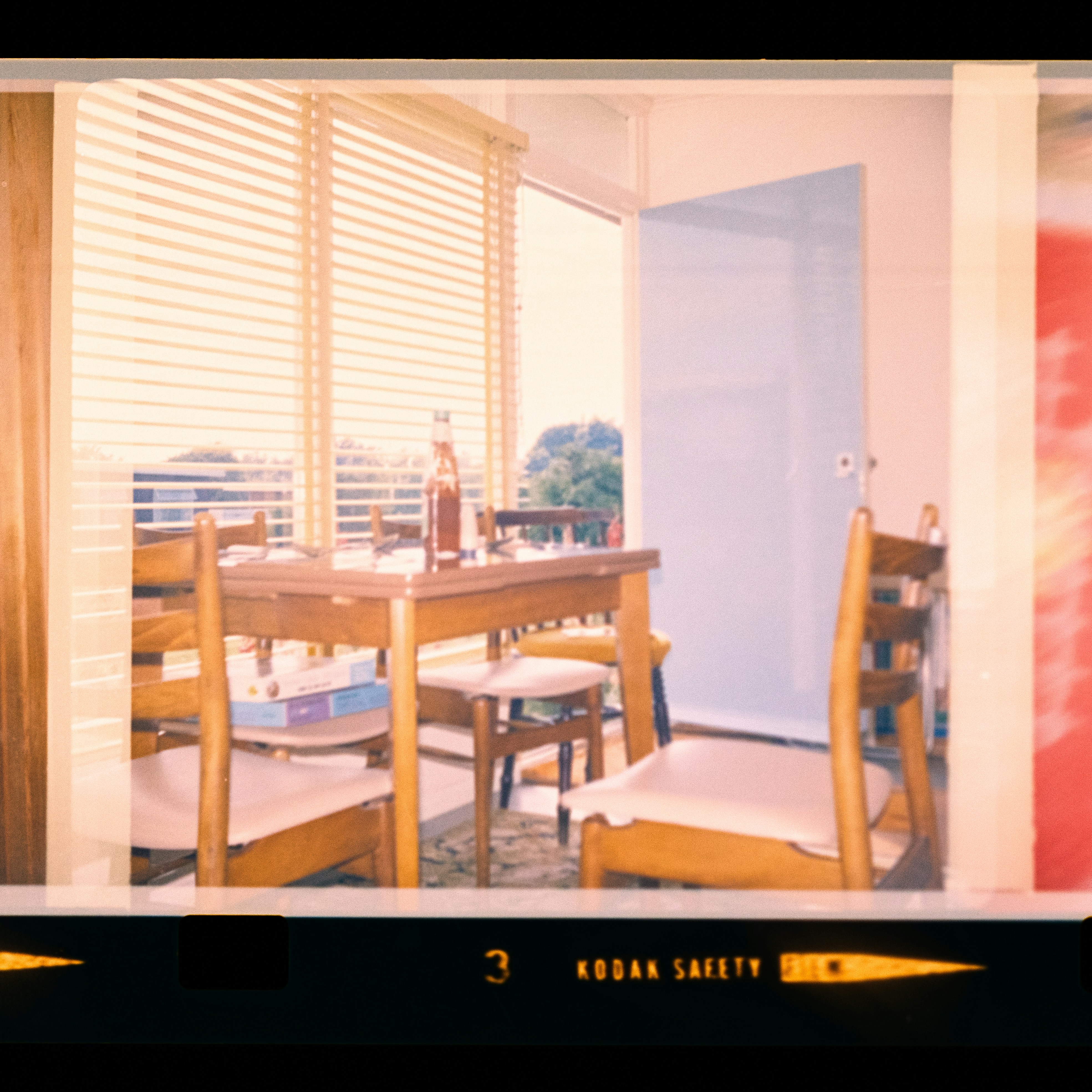 Dining table and chairs near window with blinds.