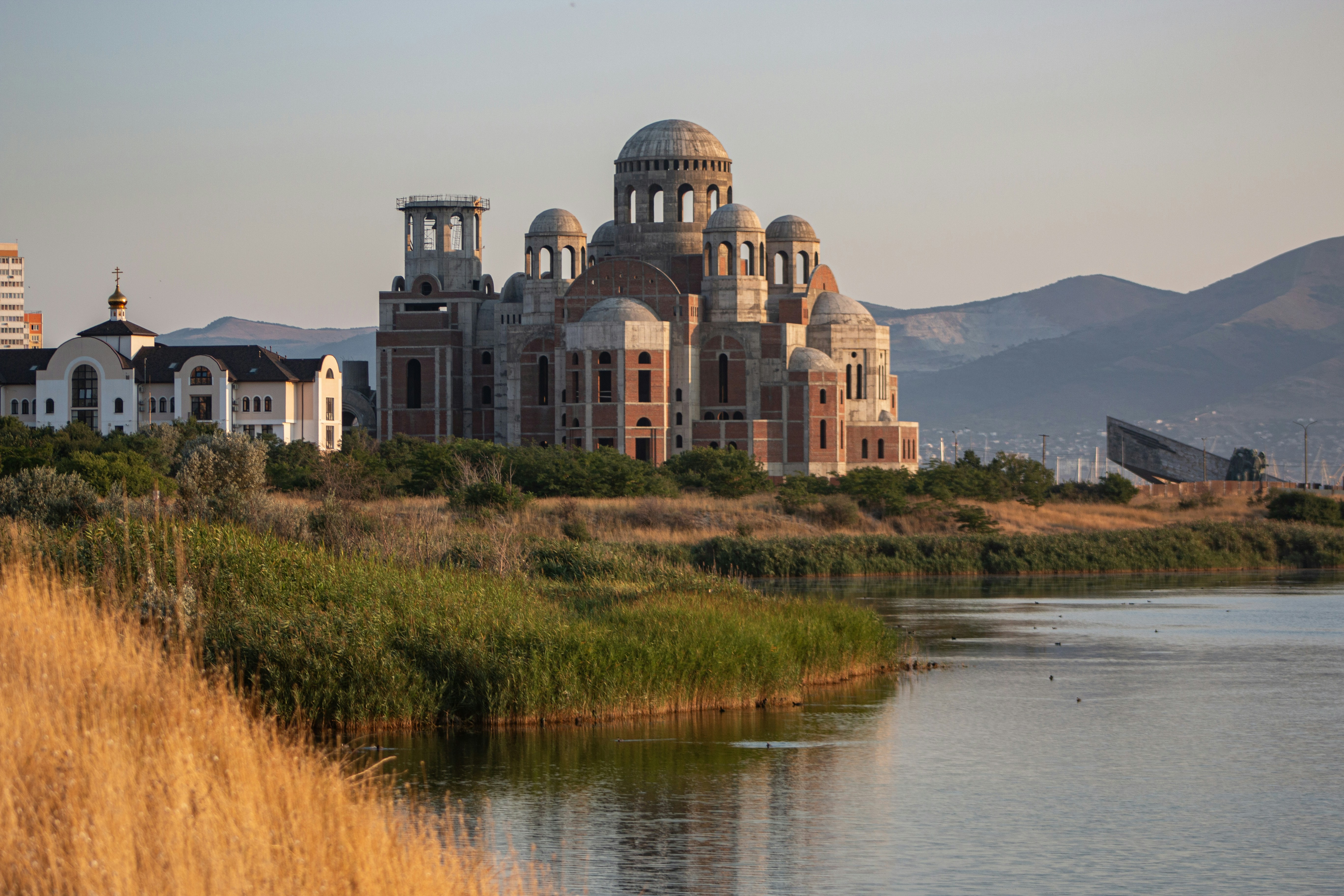 Grand building with domes beside a calm lake at sunset