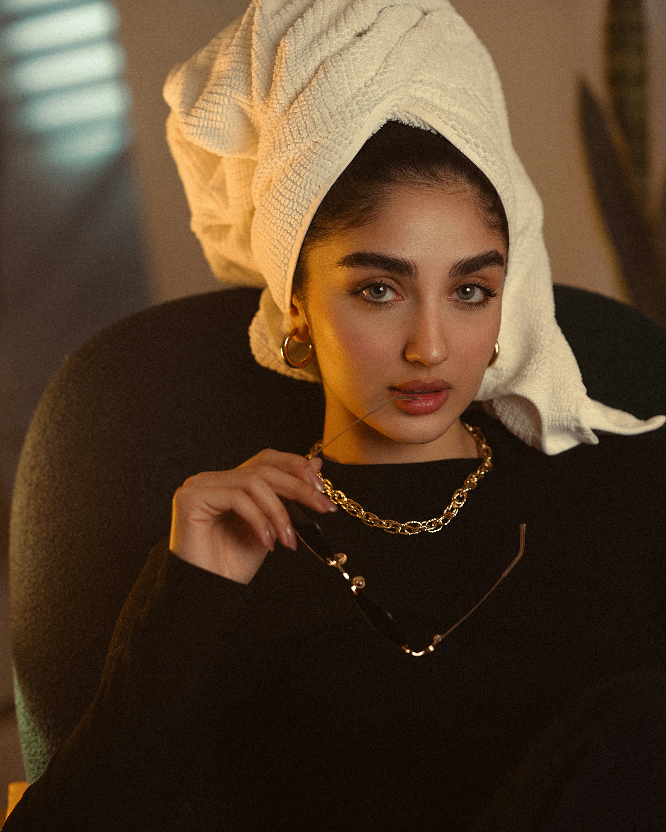 Woman with towel on head holding sunglasses