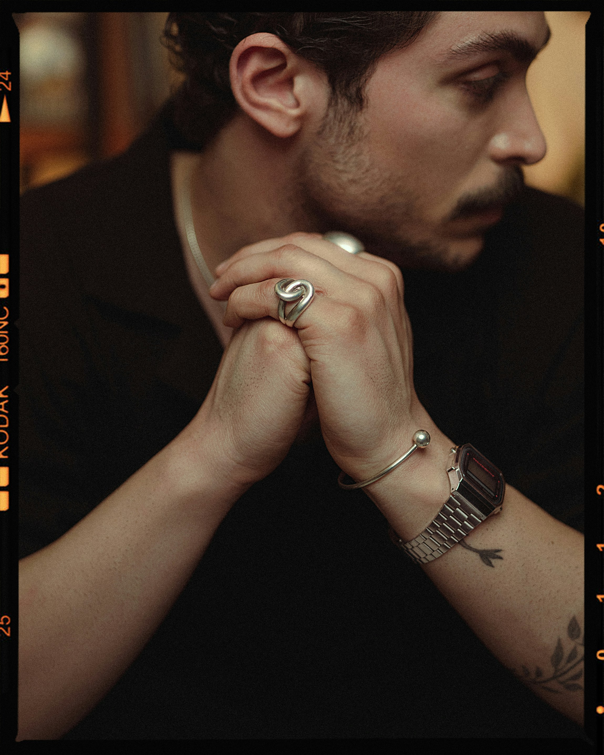 Man with hands clasped wearing rings and watch
