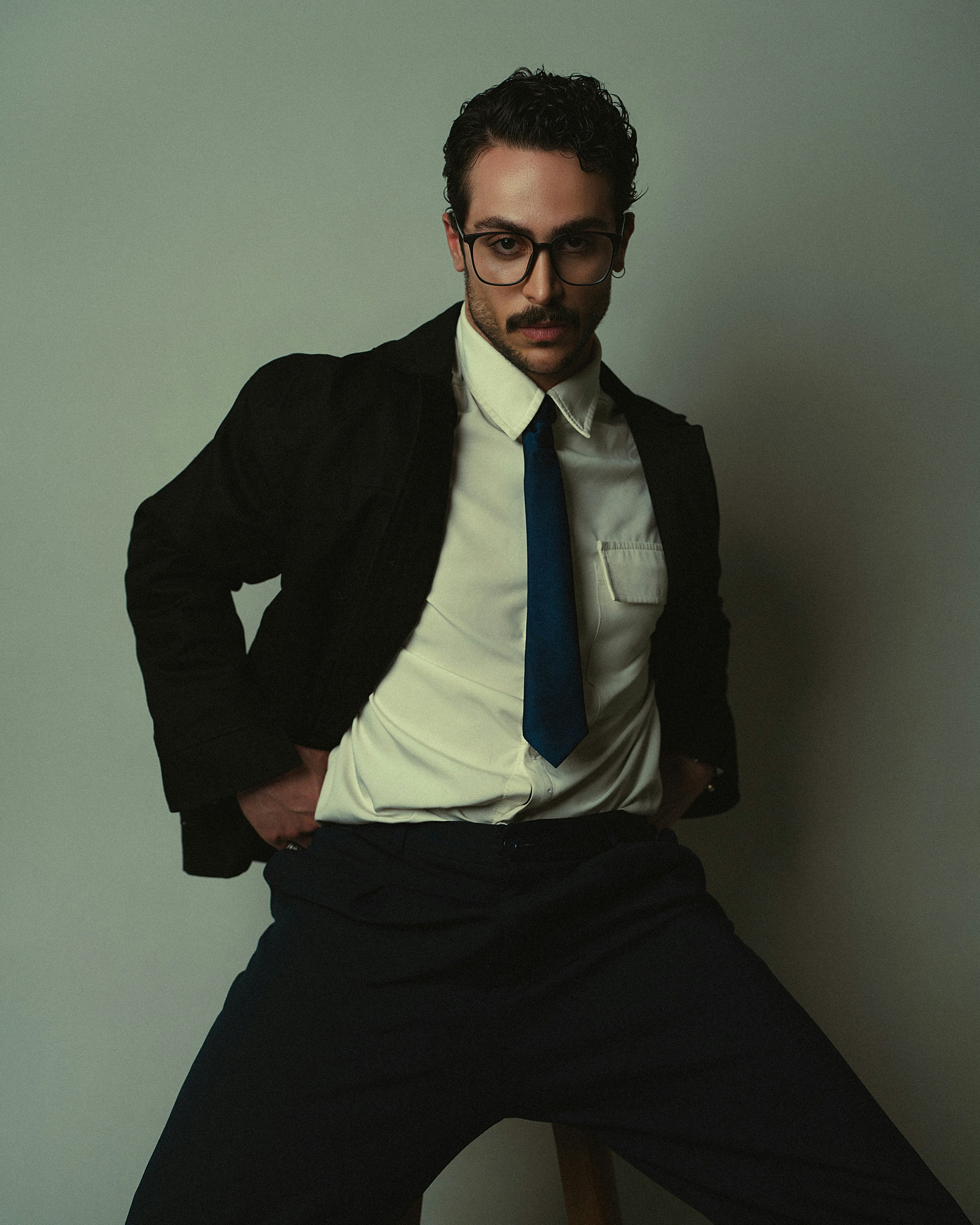 Man in a suit and tie posing against a wall