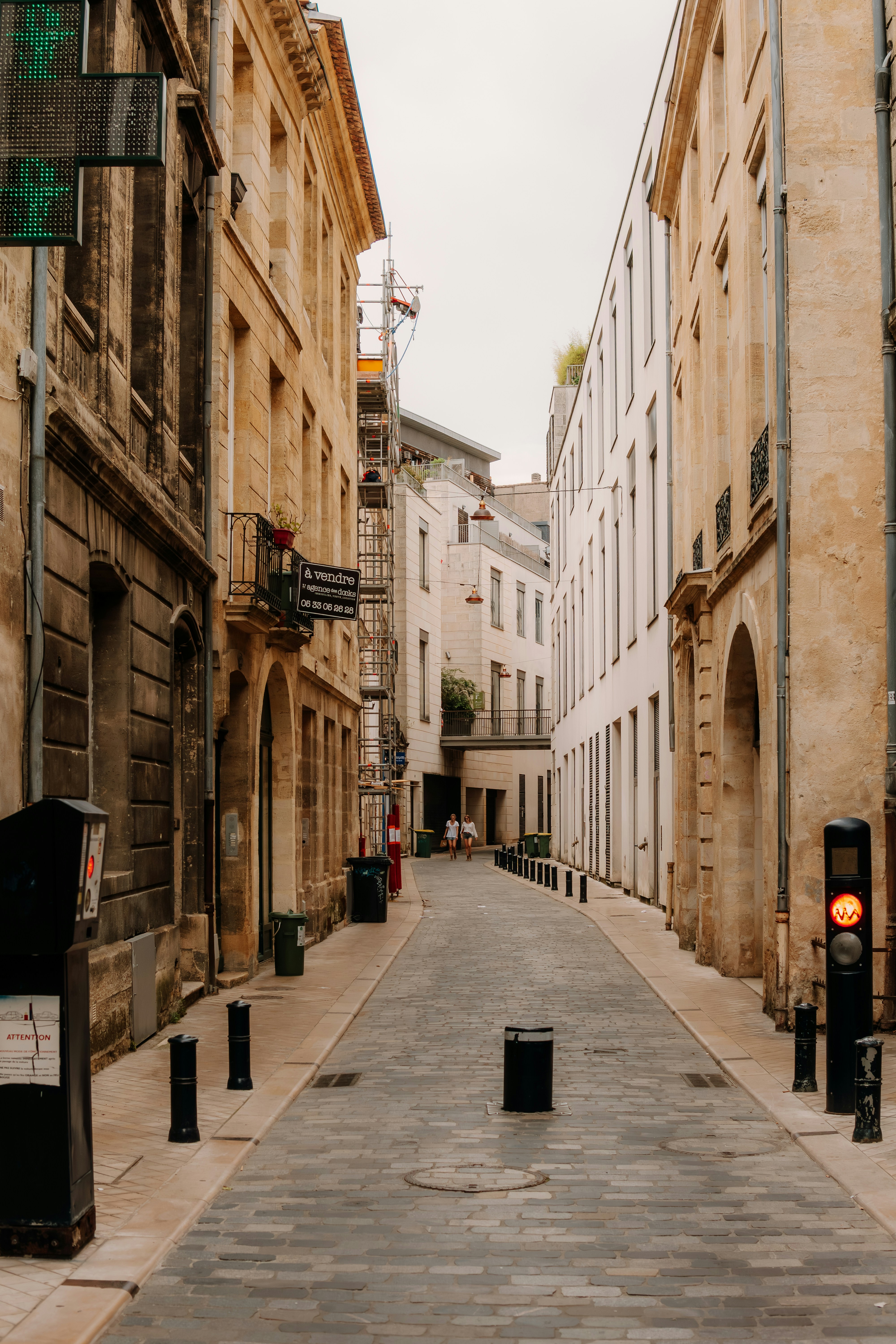 Charming narrow street flanked by historic buildings, showcasing a blend of architectural styles and a glimpse of urban life.