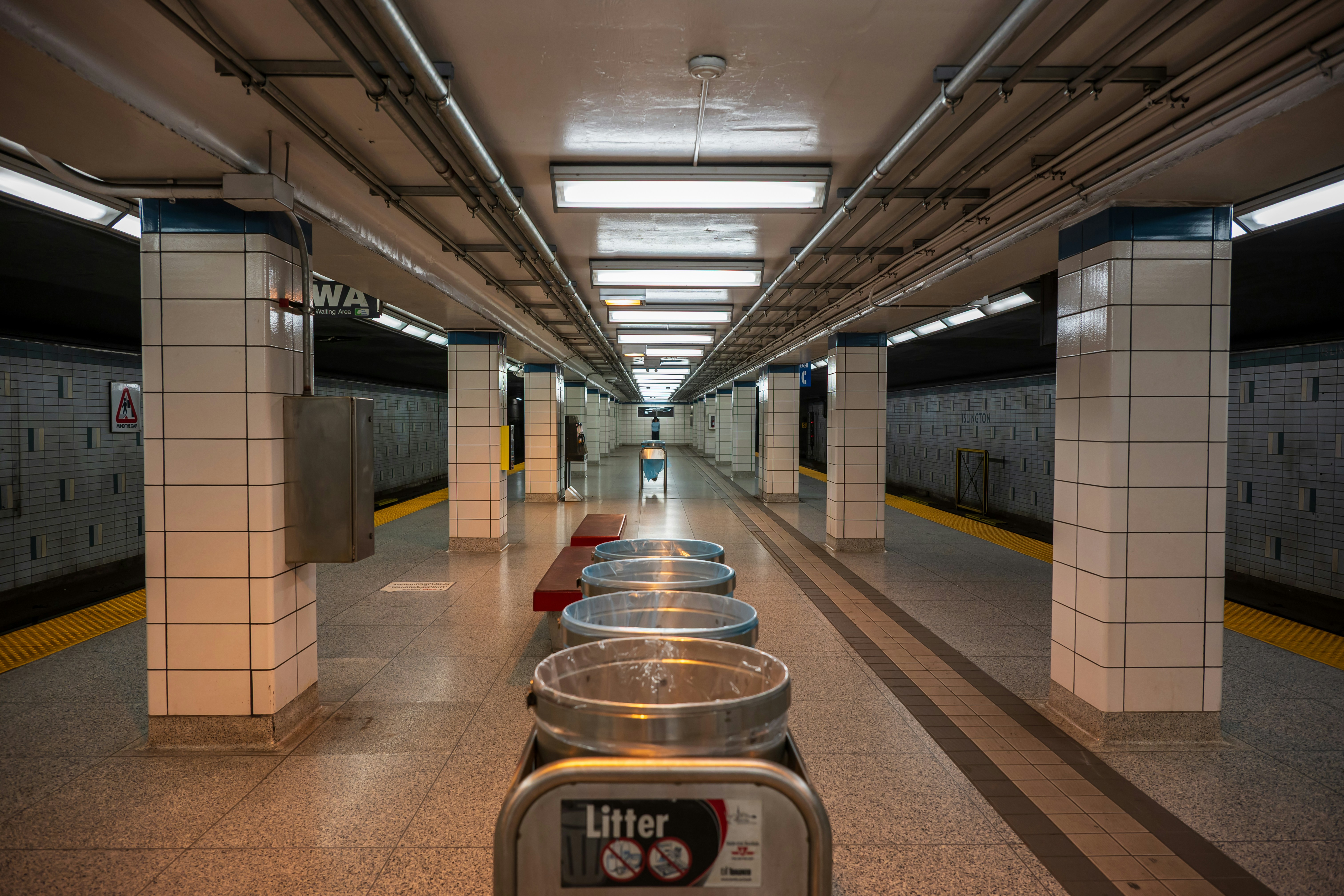 Empty subway station with train tracks and pillars.