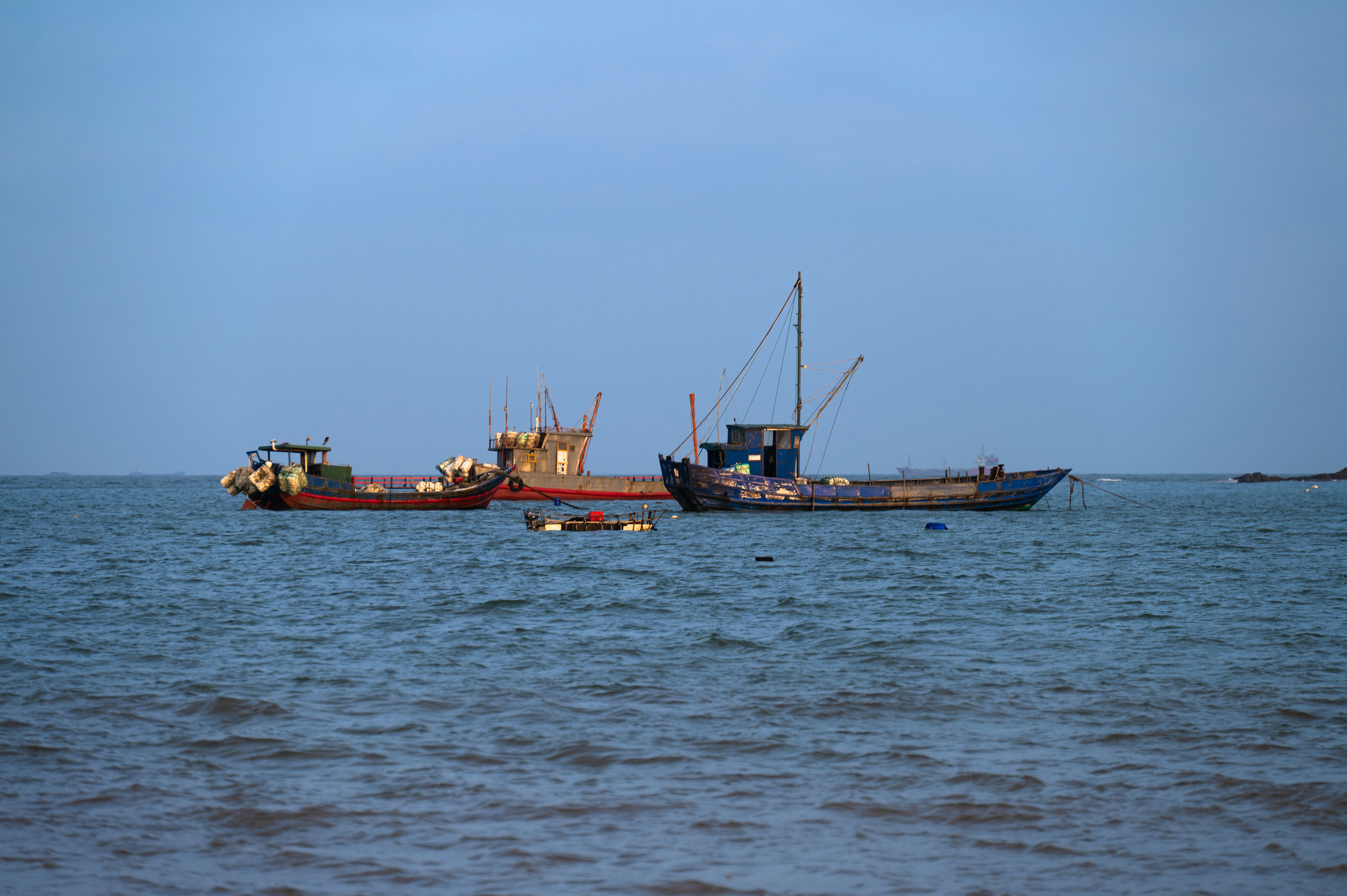 Two boats float on the calm blue ocean.