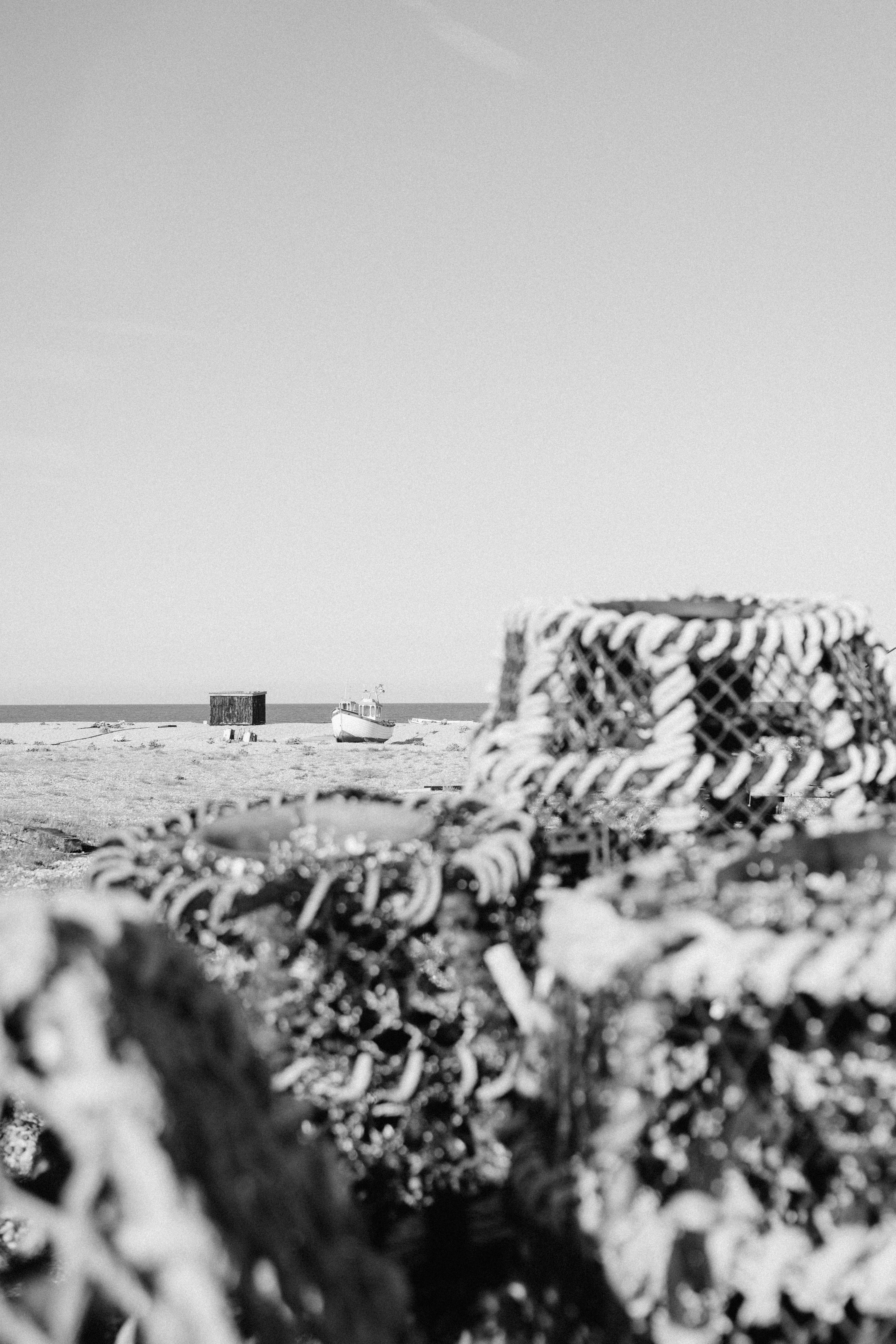 Fishing traps in the foreground with a distant boat and structures along the horizon, creating a serene coastal scene.