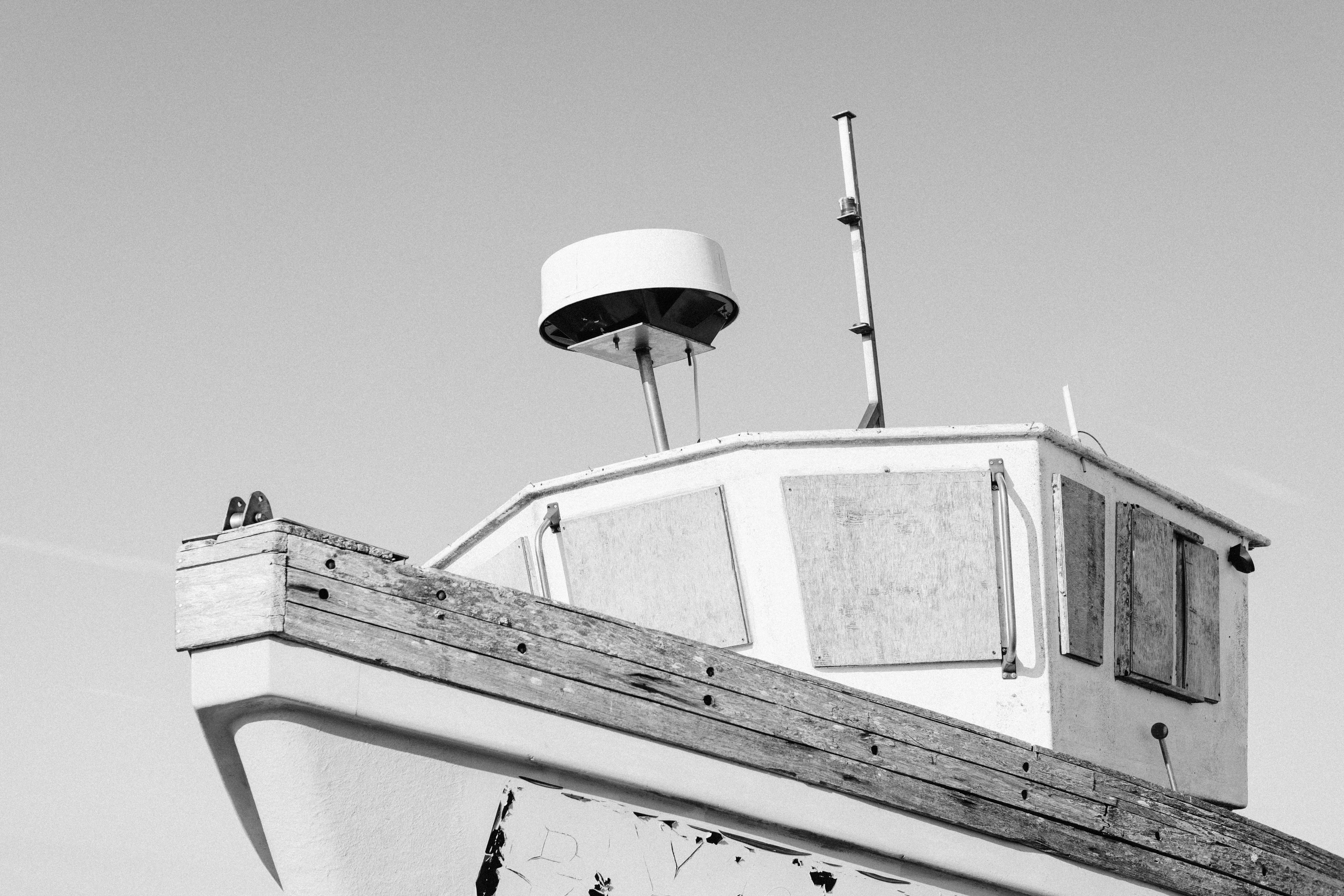 A close-up view of a weathered fishing boat, showcasing its rustic charm and intricate details against a clear sky.