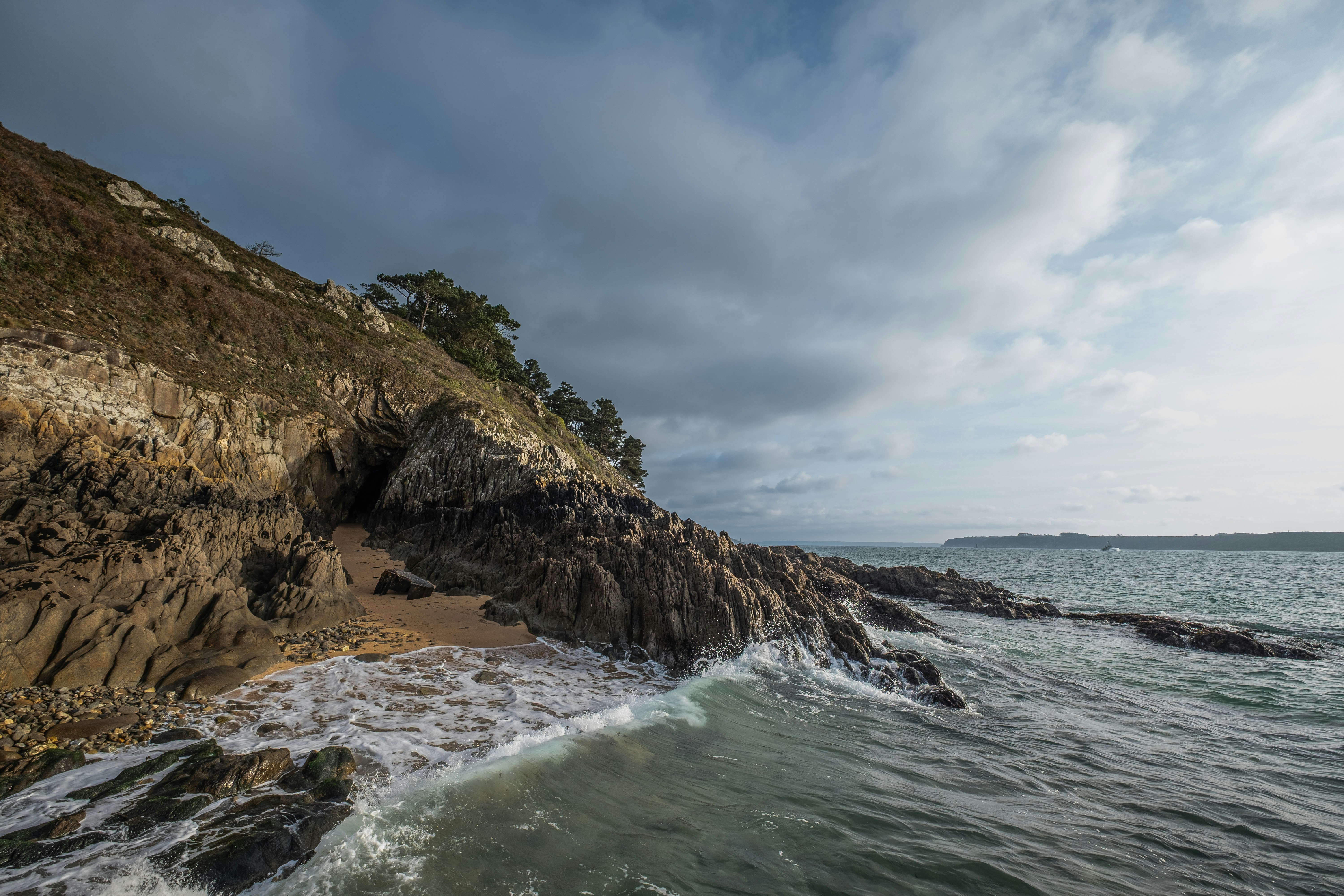 Proche du Phare du Petit Minou | Waves crash against a rocky shore under cloudy skies