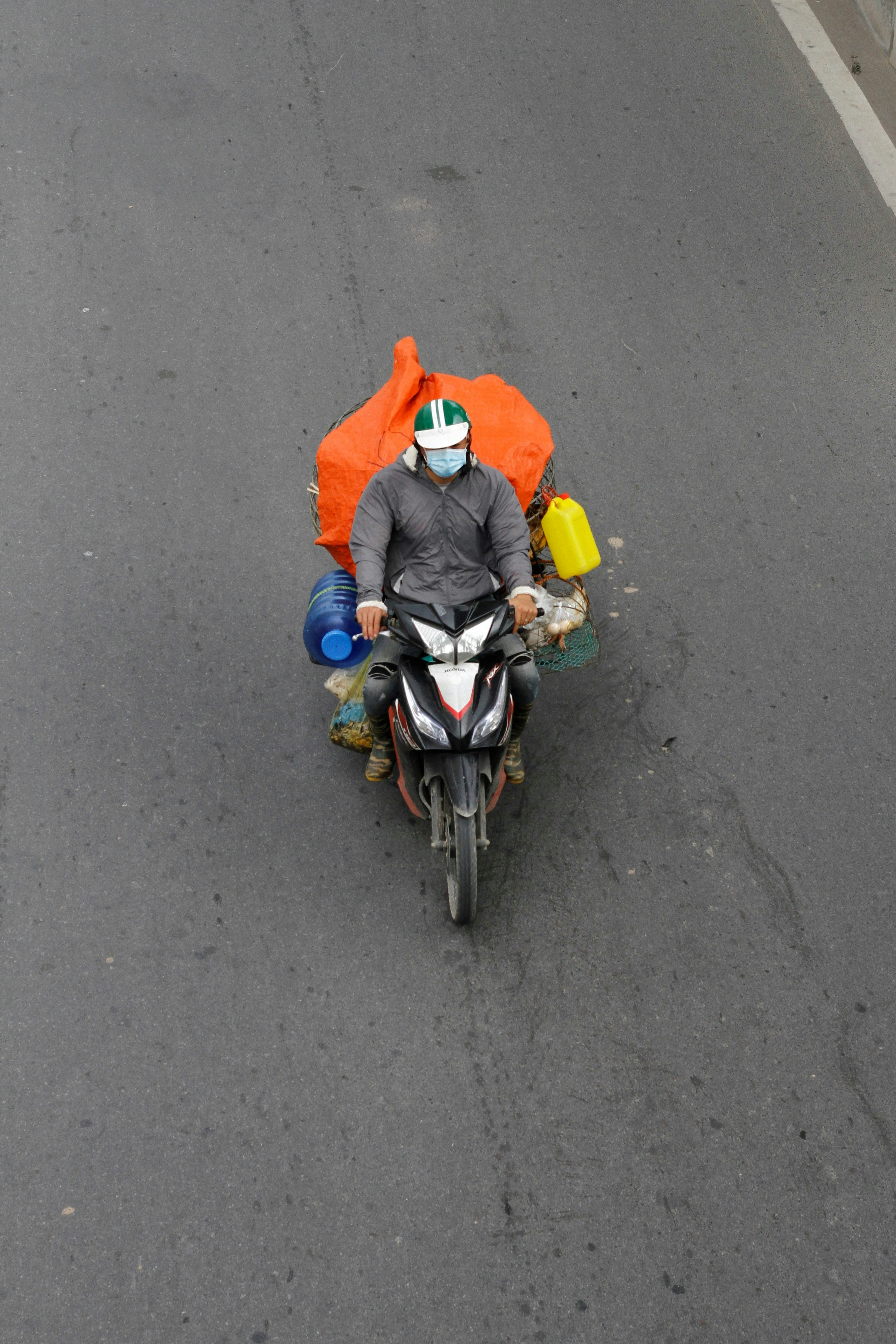 A motorcycle courier navigates city streets, transporting vibrant cargo under a protective cover. The scene reflects the hustle of urban life.