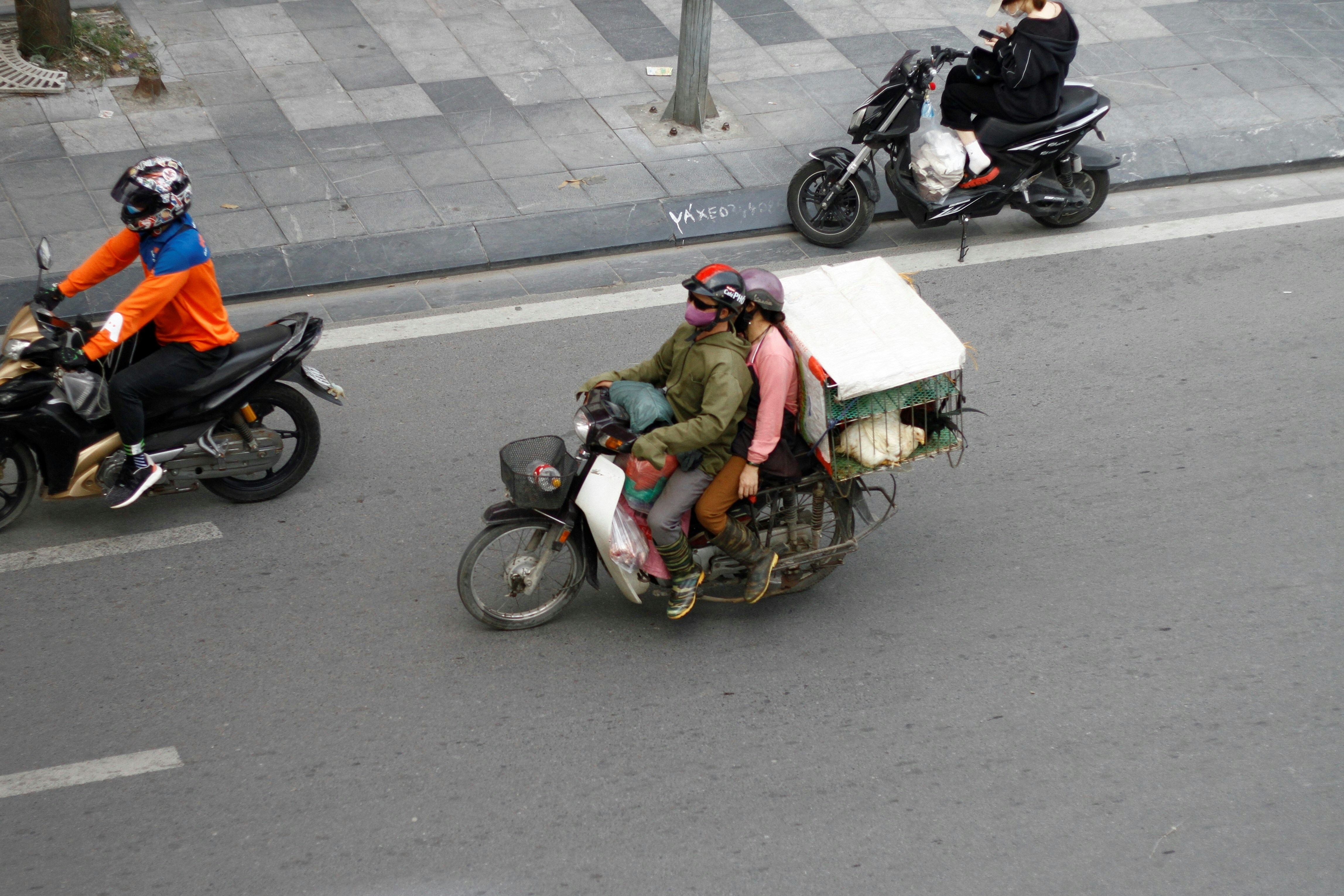 Two passengers on a motorcycle navigate a busy city street, showcasing the practicality of motorbike transport in urban environments.