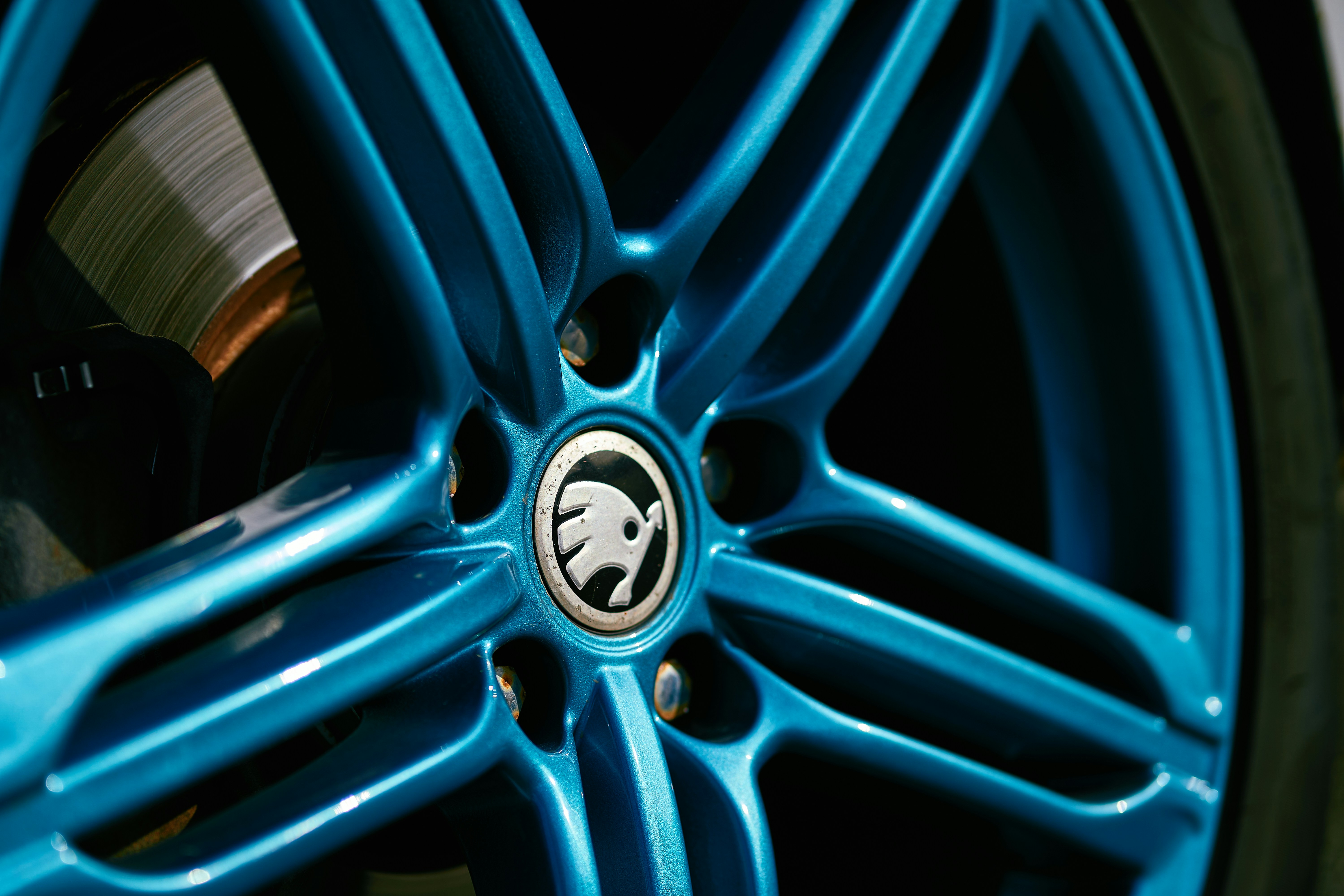 Close-up of a shiny blue car wheel with logo.