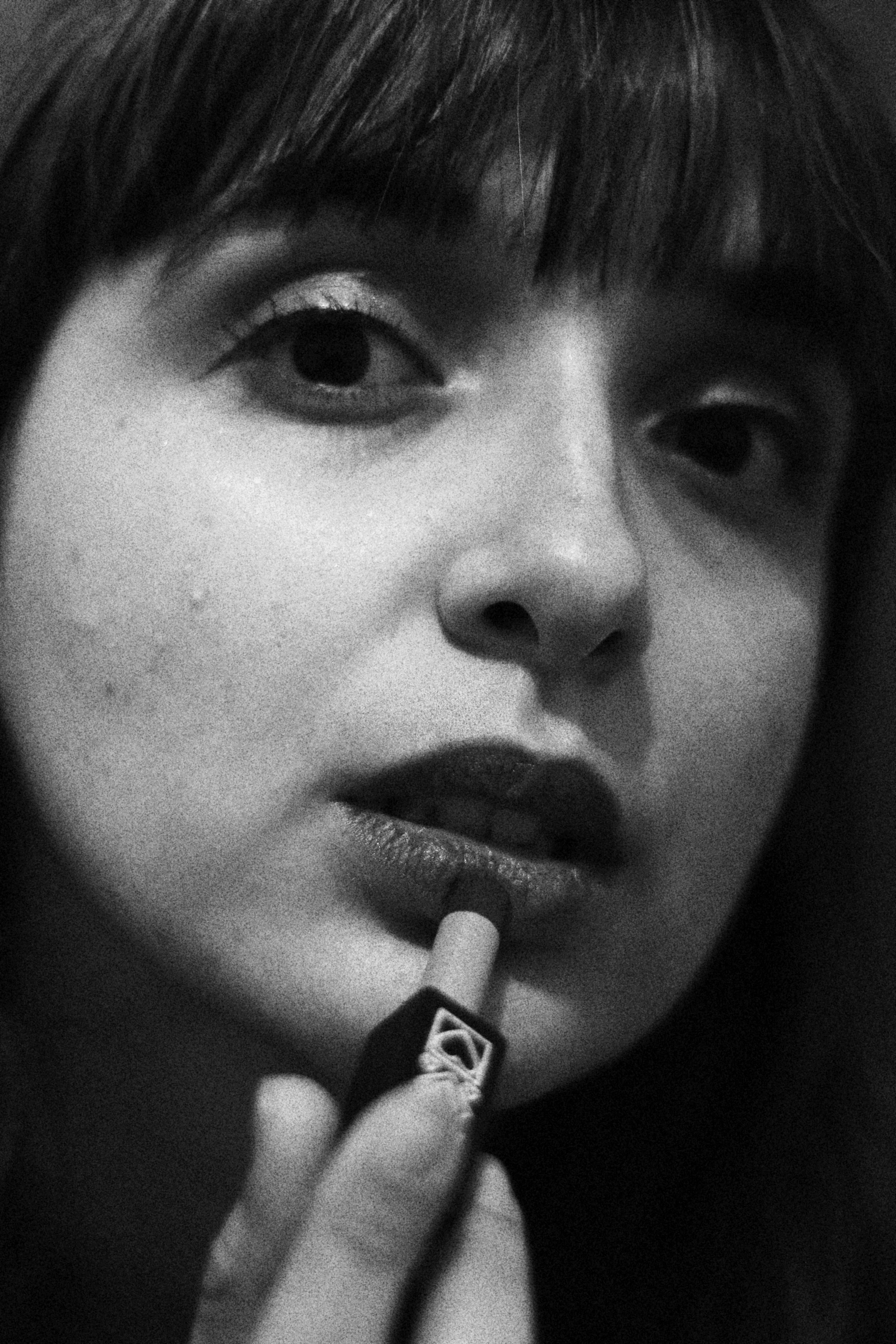 A young woman applying lipstick, showcasing her focused expression and the delicate process of enhancing her features.