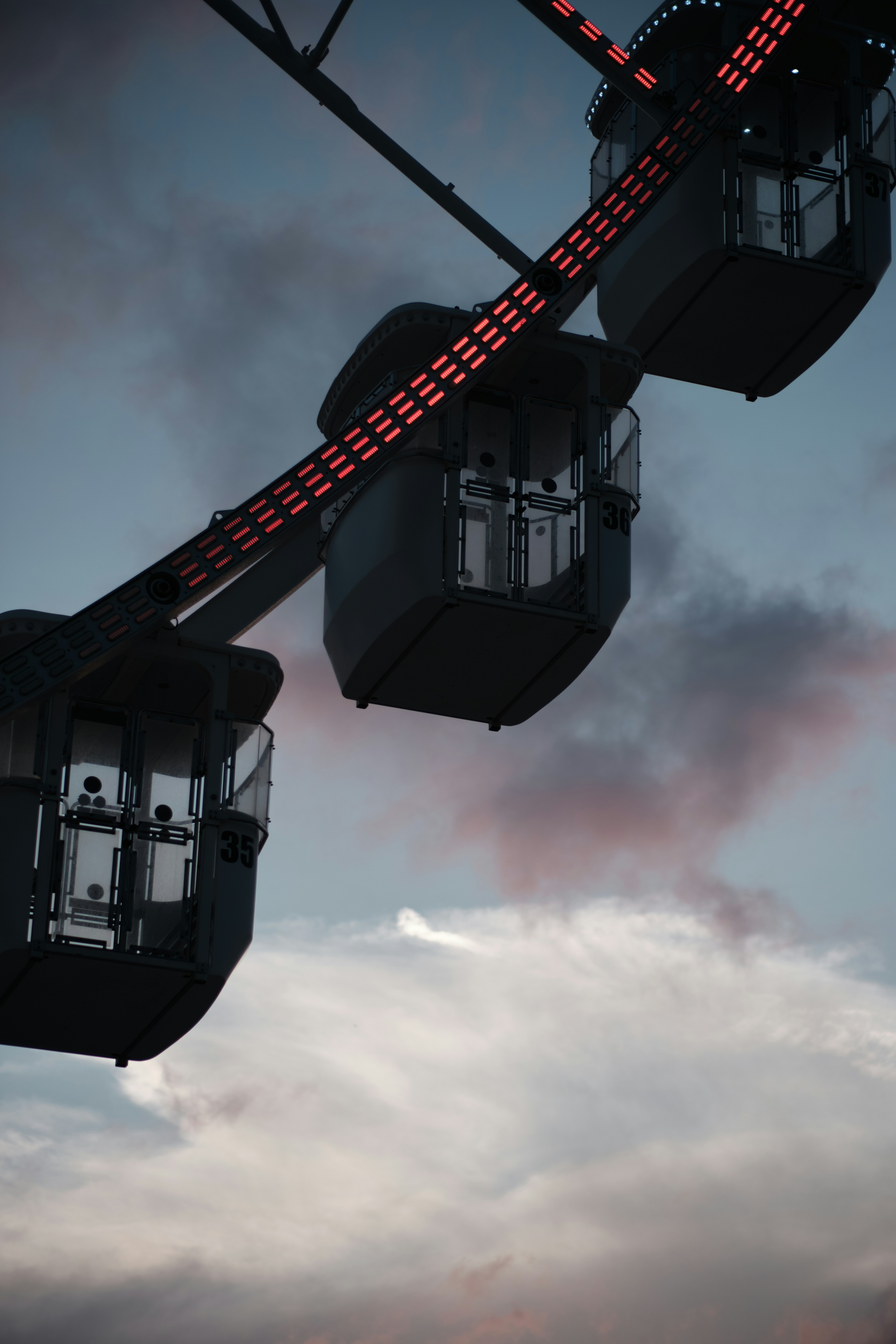 Ferris wheel cabins at dusk. Close-up of ferris wheel cabins silhouetted against the evening sky with soft clouds and pastel tones. | Ferris wheel cabins against a cloudy twilight sky.
