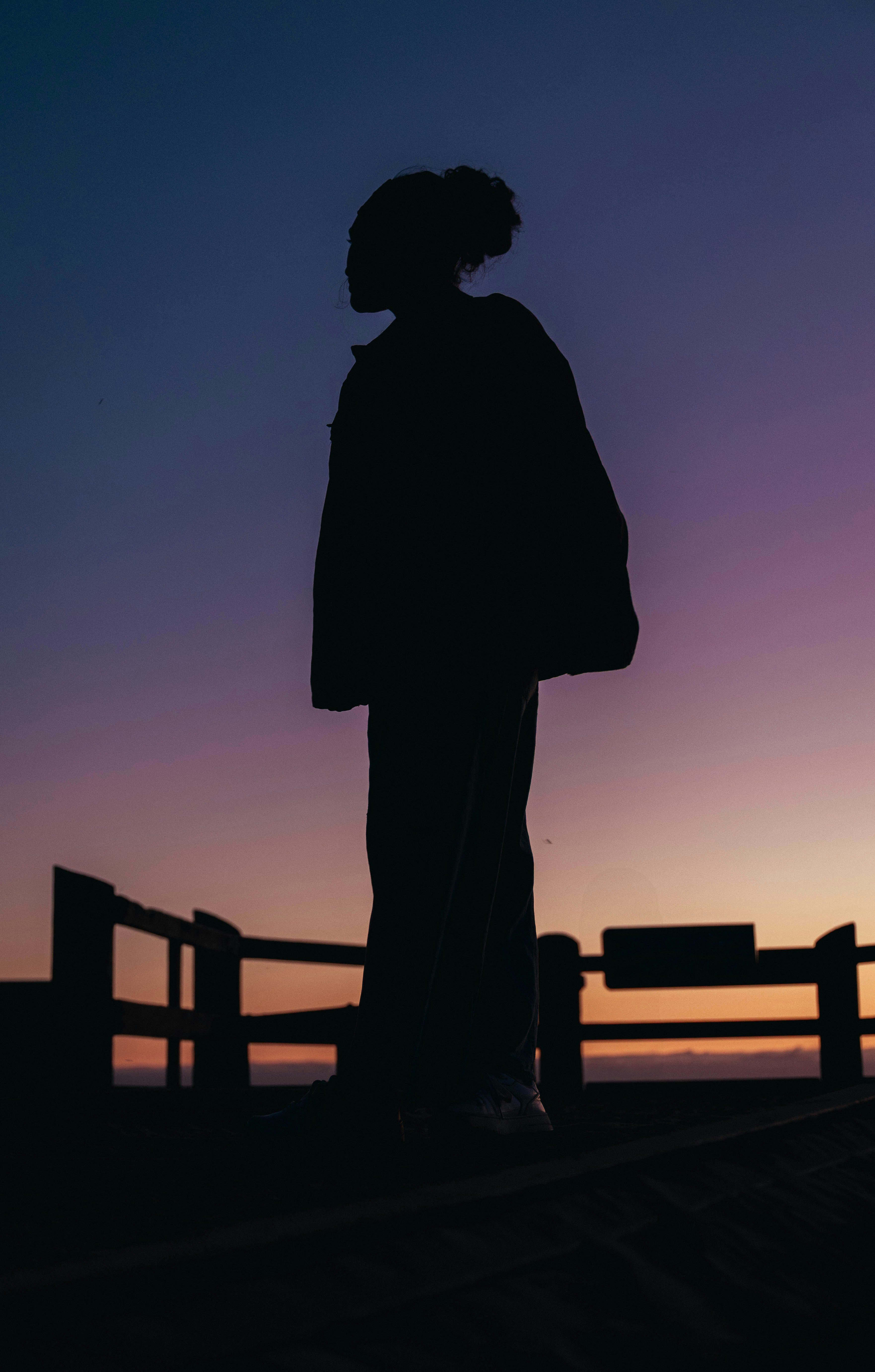 Silhouette of a person against a colorful twilight sky