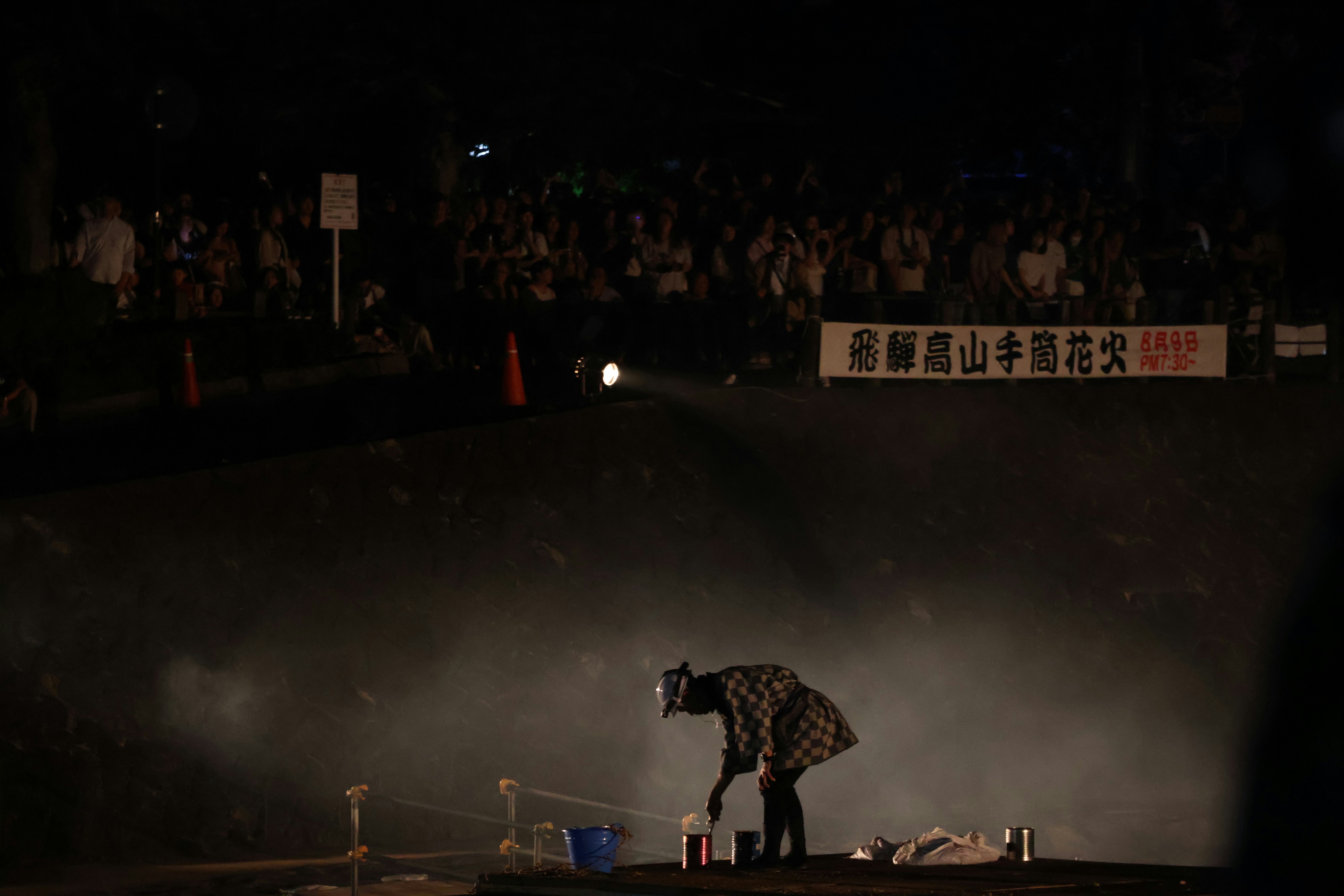 Spotlit Resolve: A Lone Performer Emerges Through Smoke at Night