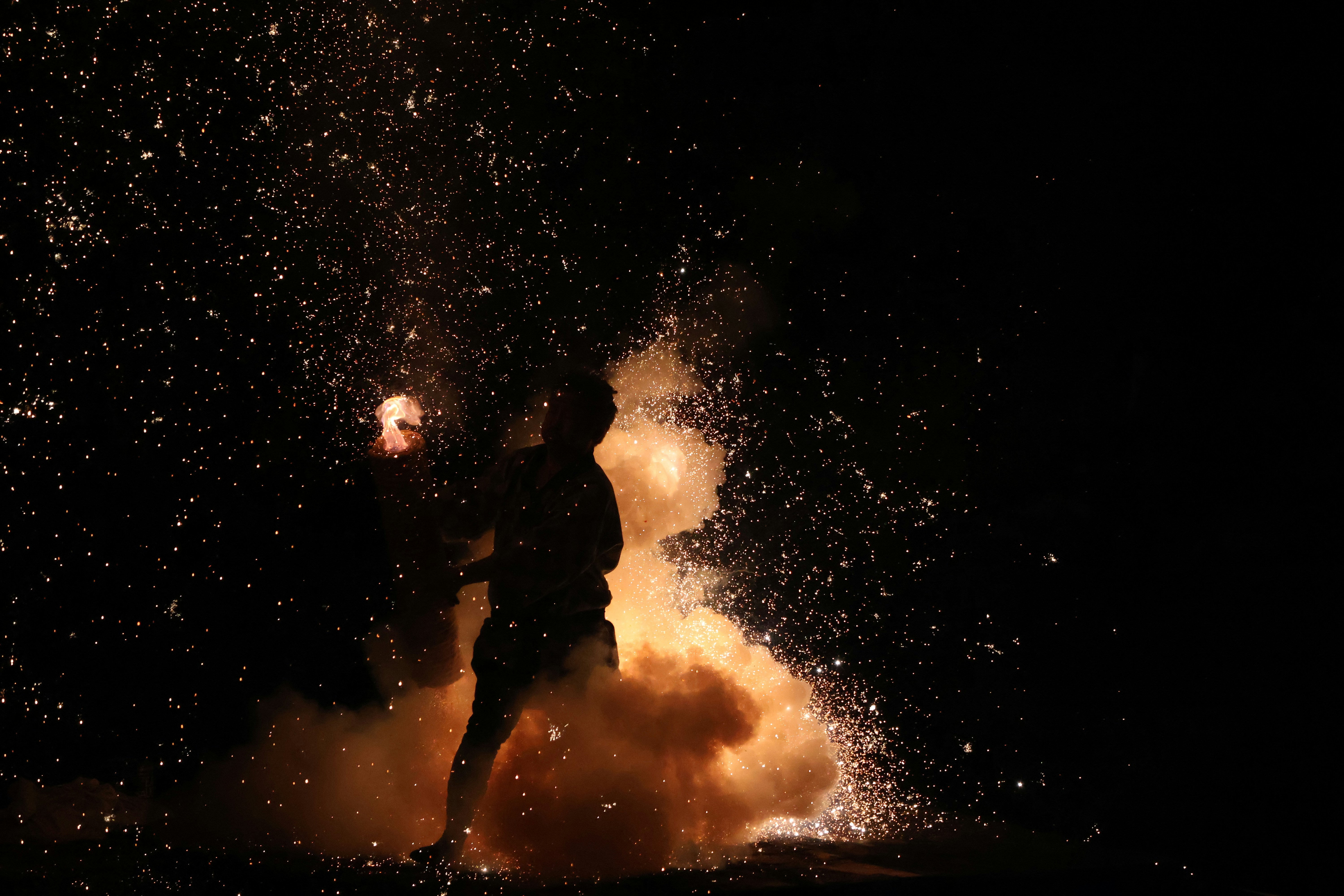Handheld fireworks in a Hida-Takayama summer event | Man standing near a bright bonfire at night