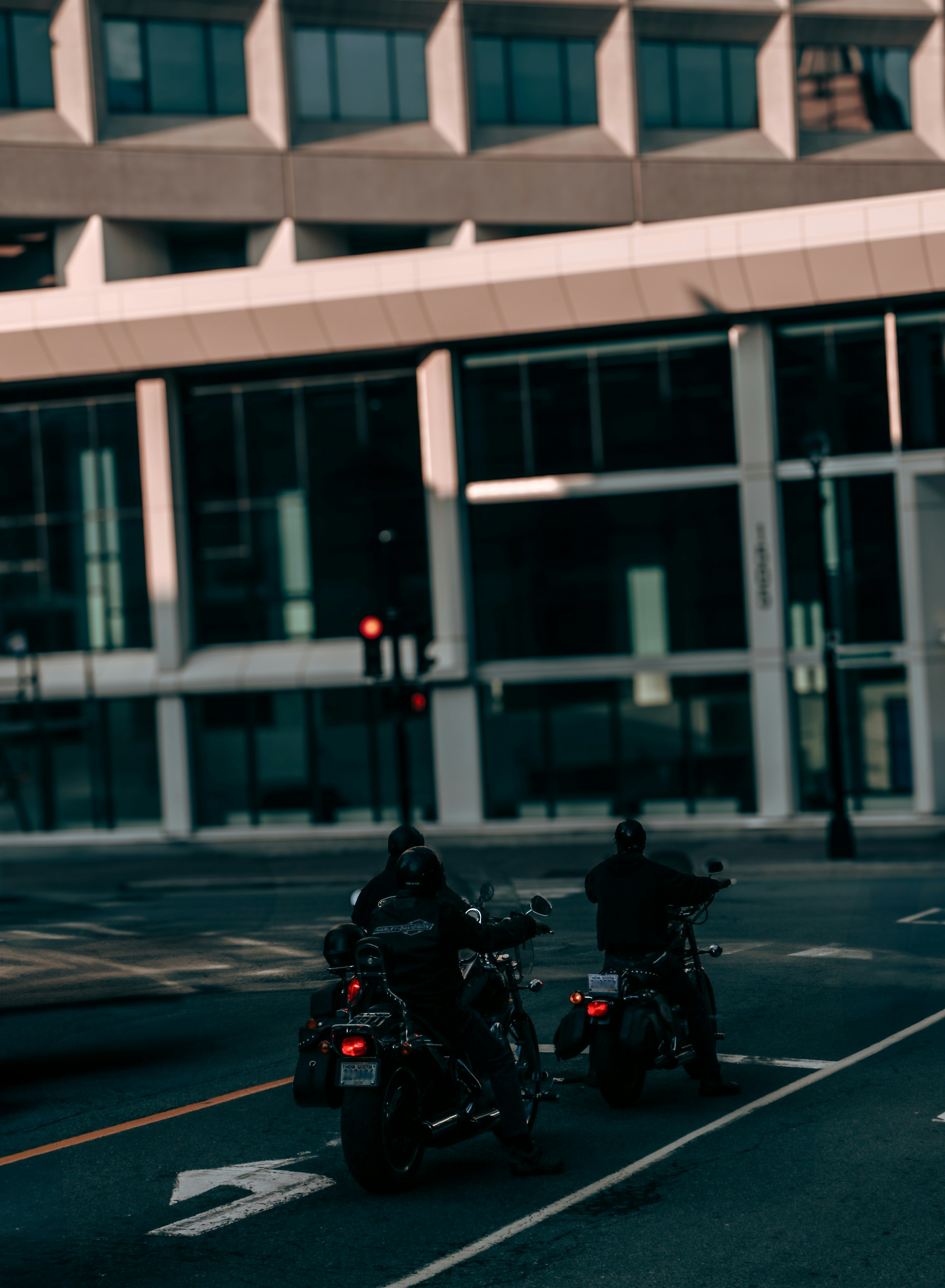Two motorcyclists ride down a city street.