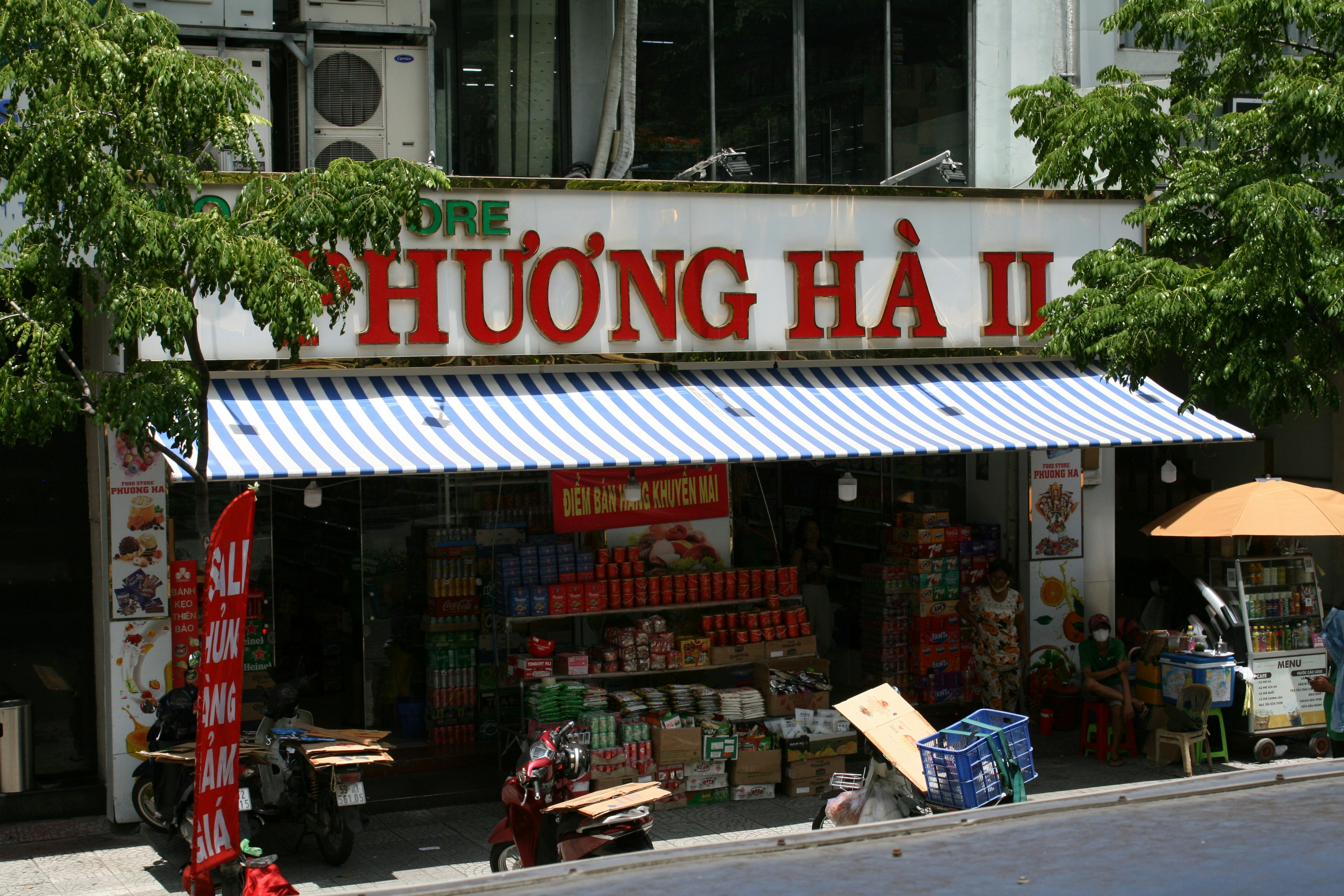 Vibrant storefront of a local market featuring colorful signage and various goods displayed. The scene captures the essence of daily life in a bustling neighborhood.