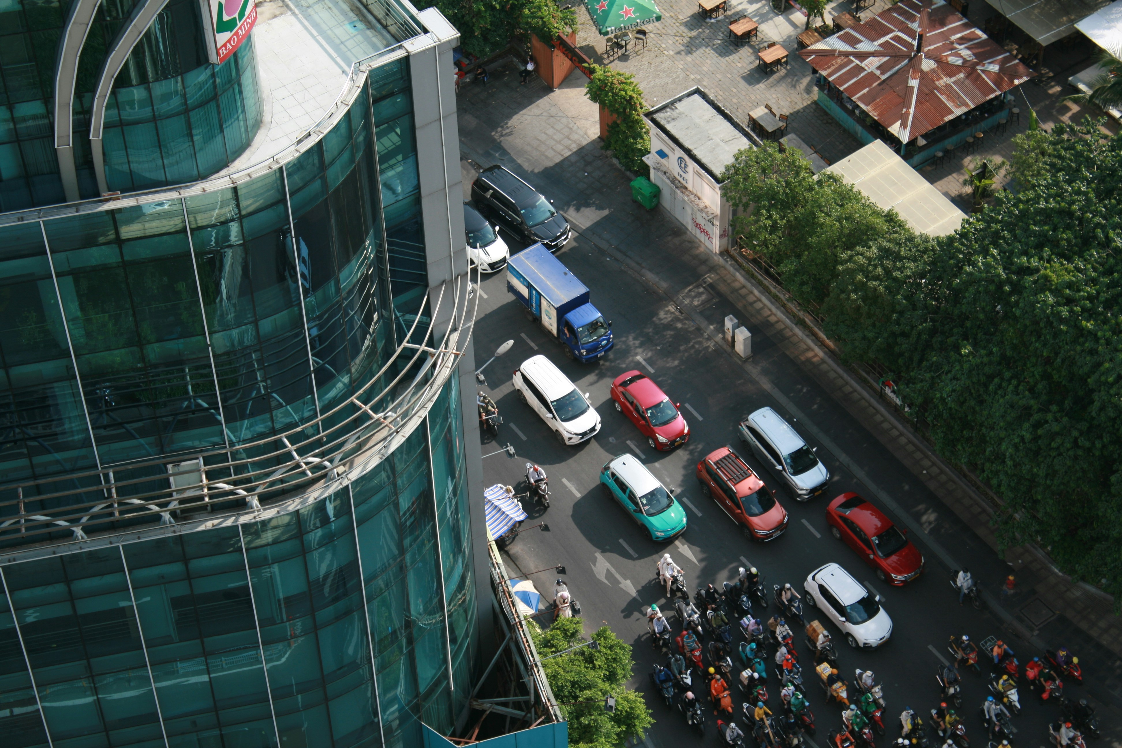 Busy street with cars and motorcycles near modern building