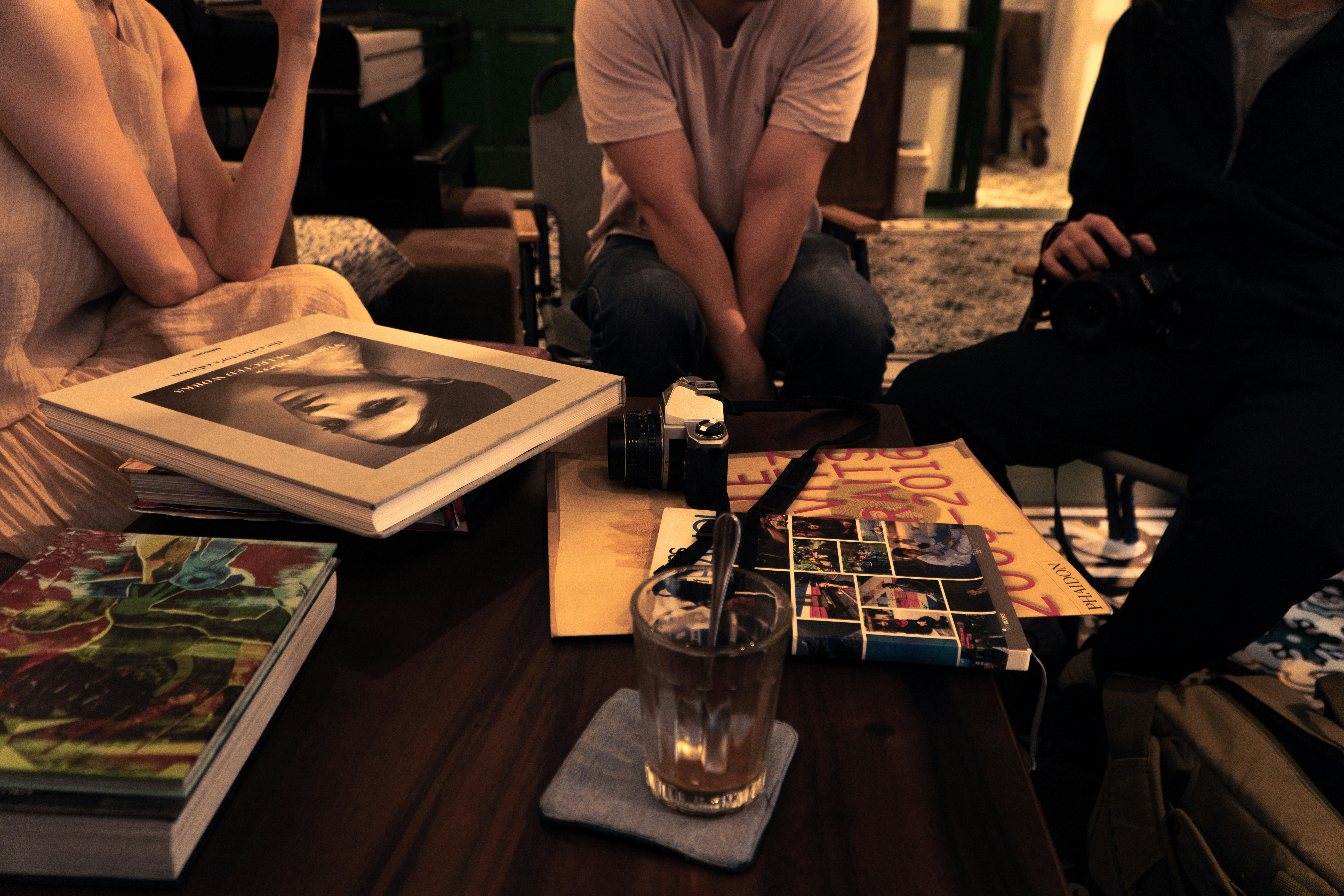 People gathered around a table with drinks and books.