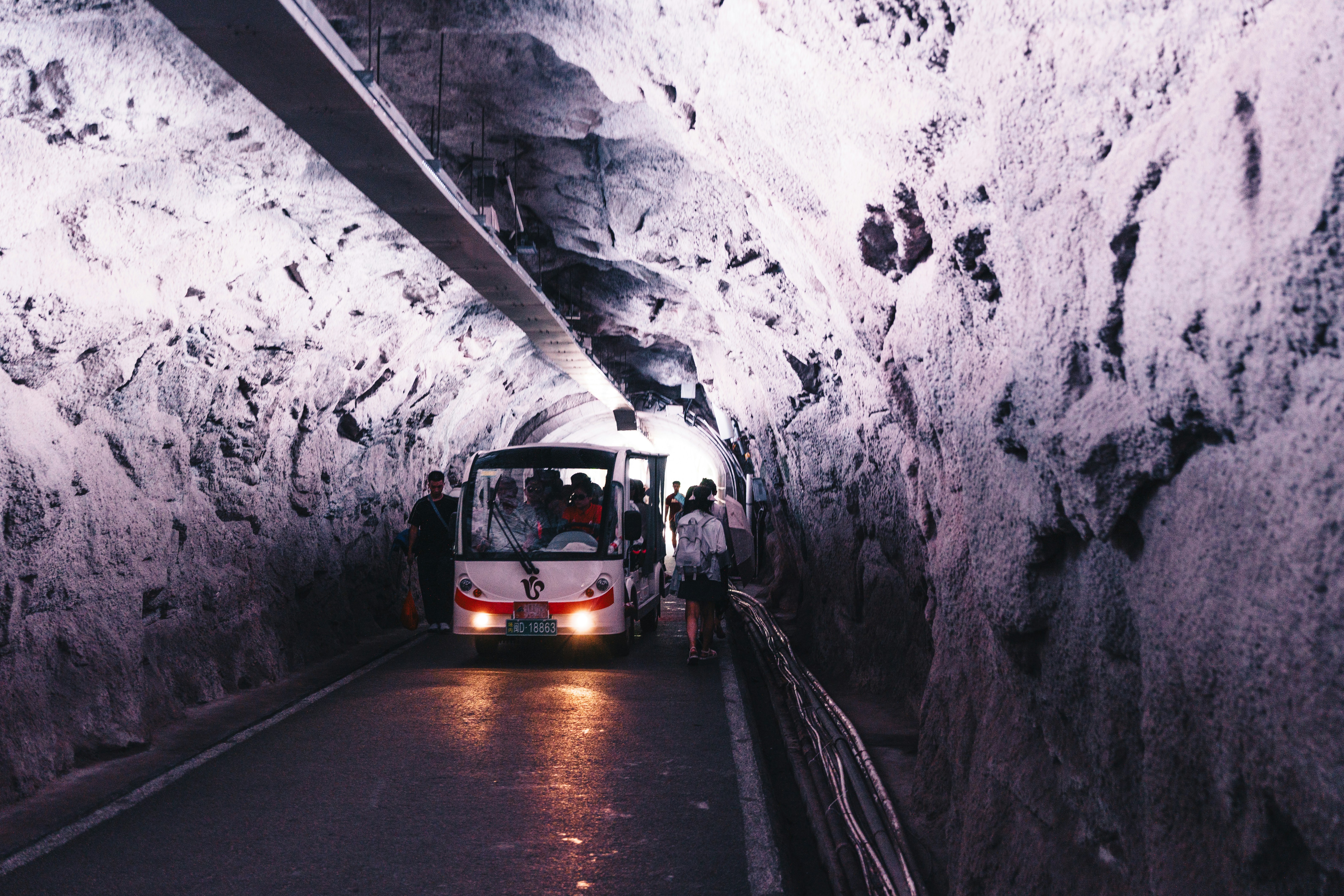 Tour bus driving through a rocky tunnel