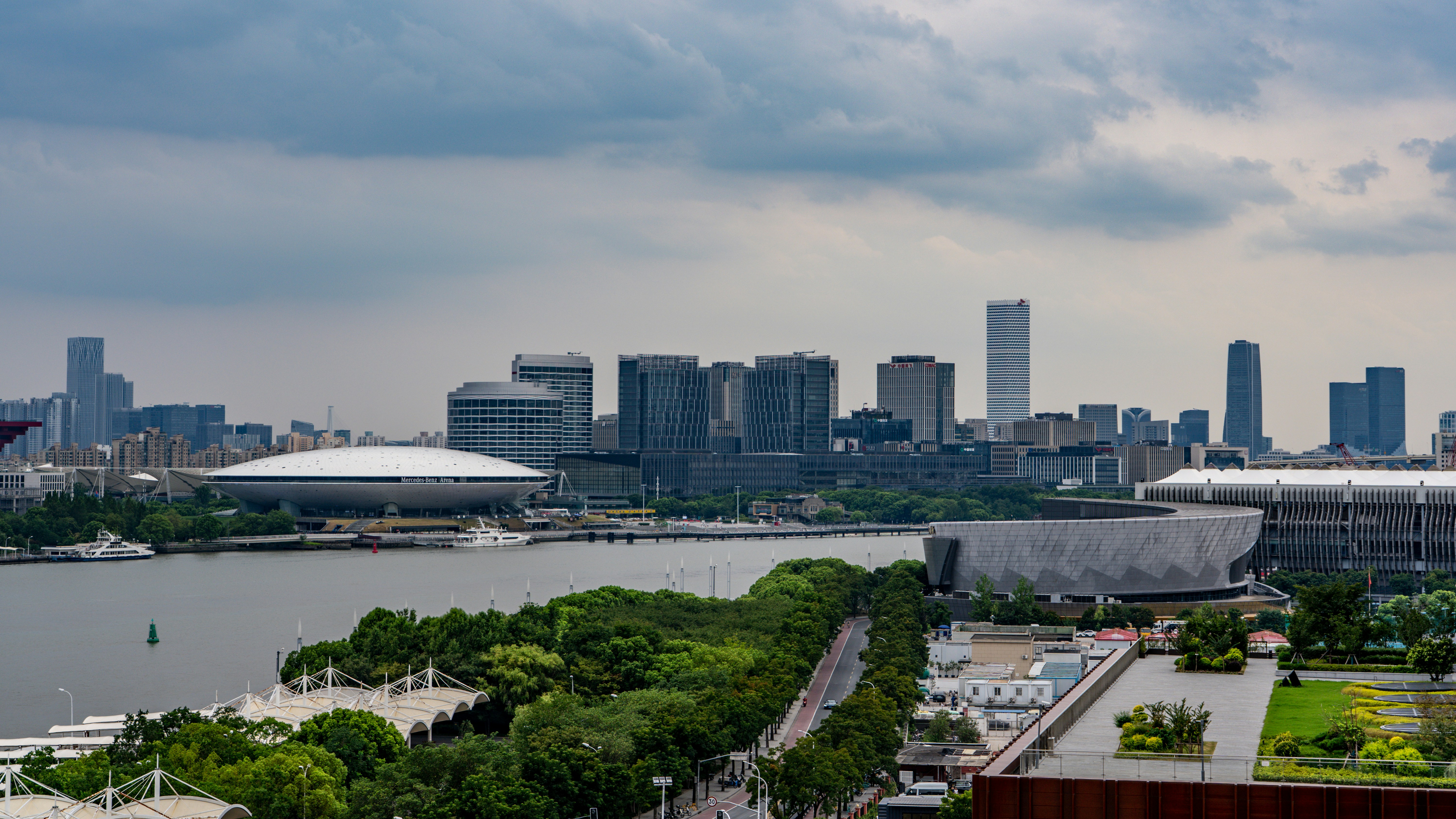 Modern cityscape with river and stadiums under cloudy sky