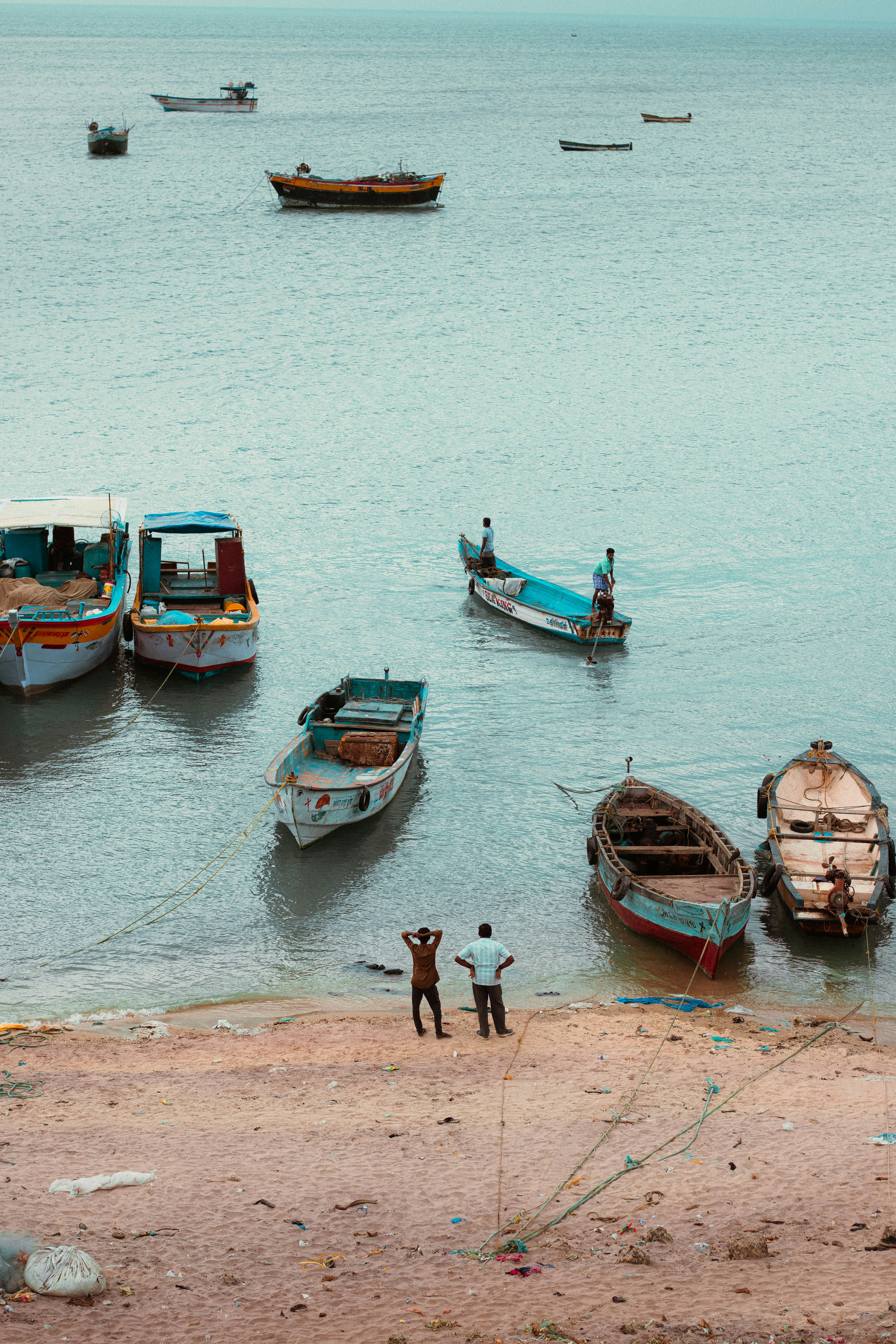 chill | Boats moored near a sandy shore with two men observing.