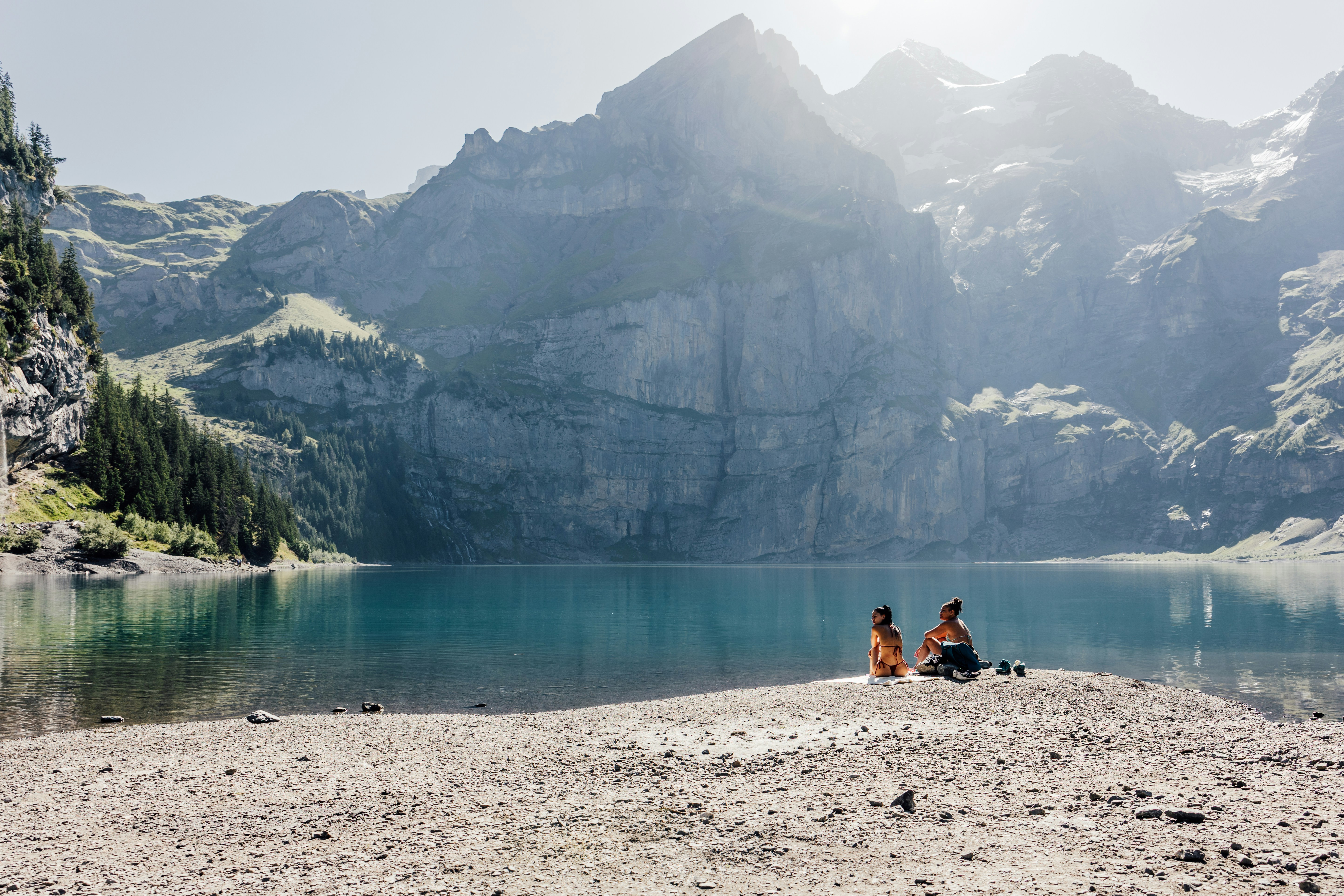 Two people sitting by a serene mountain lake