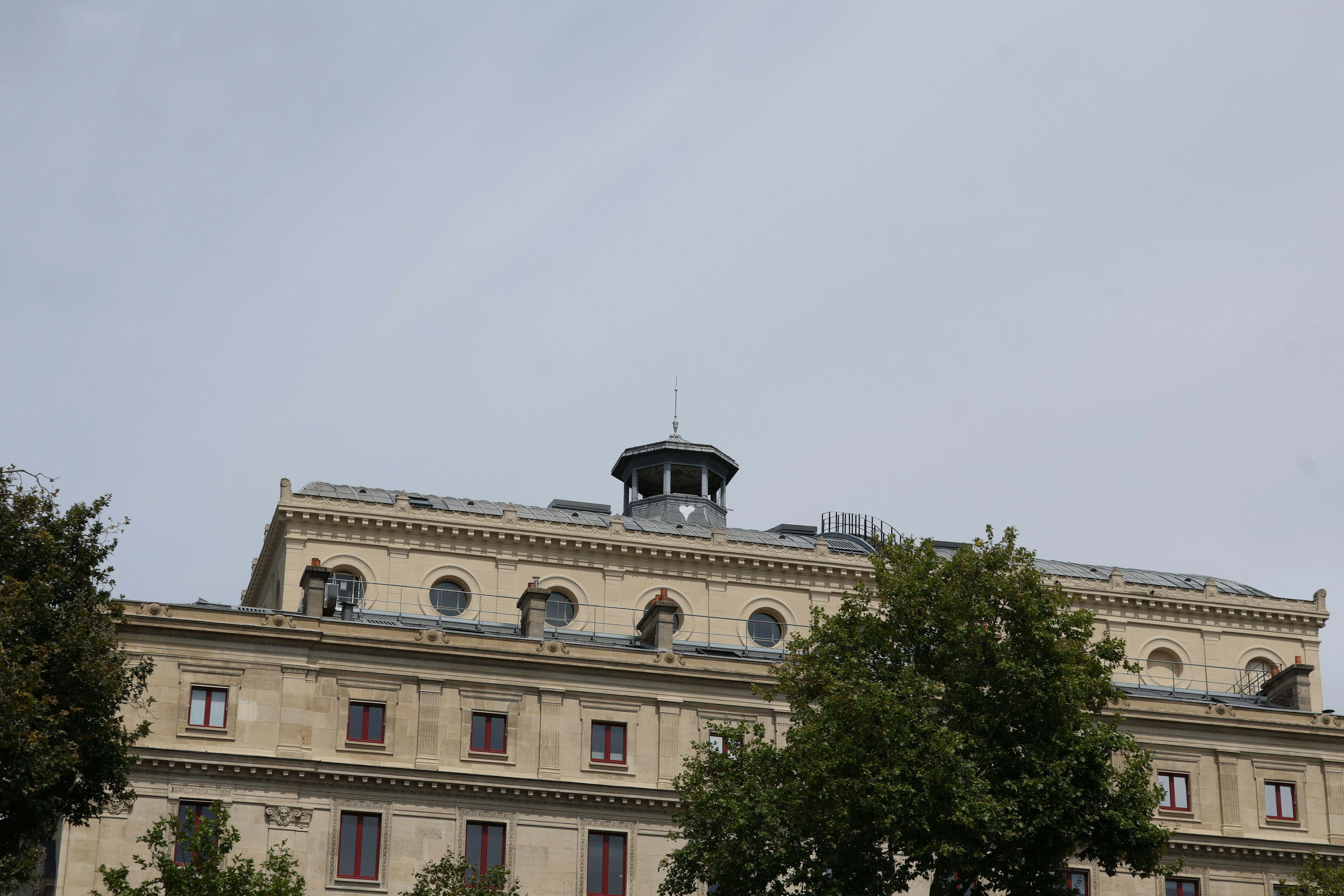 Historic building with trees under a cloudy sky