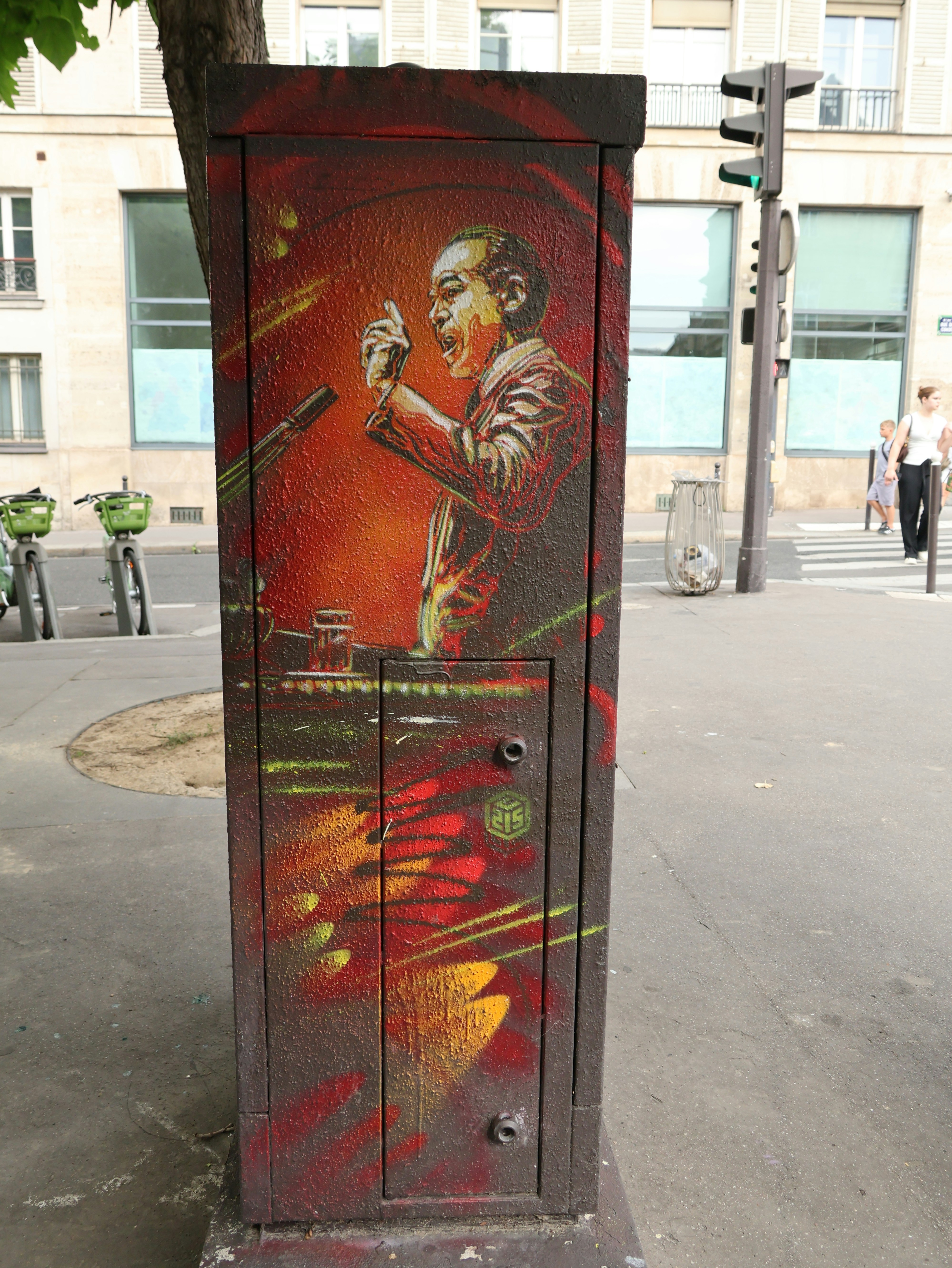 Vibrant street art depicting a passionate figure at a microphone, surrounded by dynamic colors and patterns. The artwork transforms an ordinary utility box into a canvas of creativity.