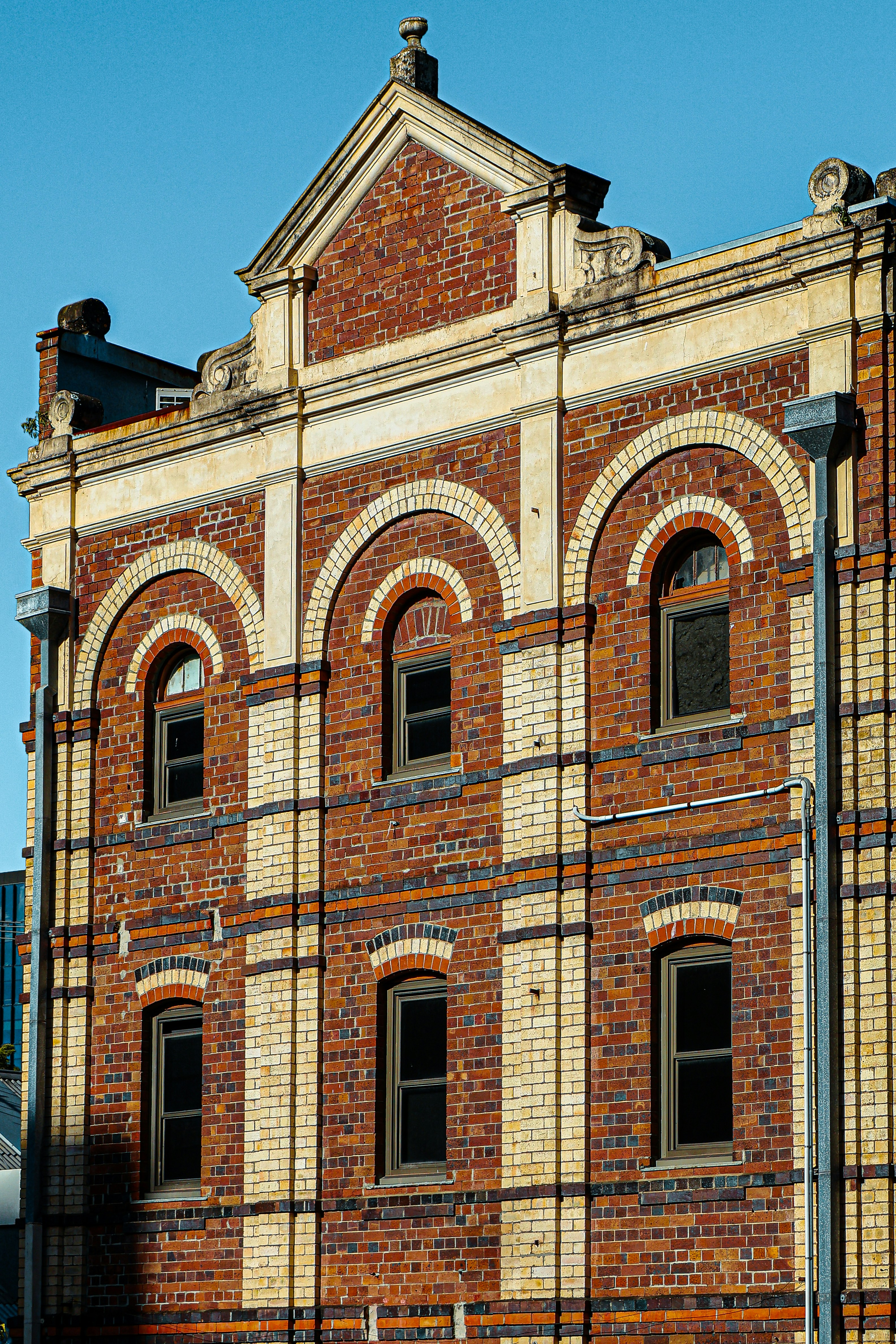 Old Mill Barracks | Old brick building with arched windows under blue sky.