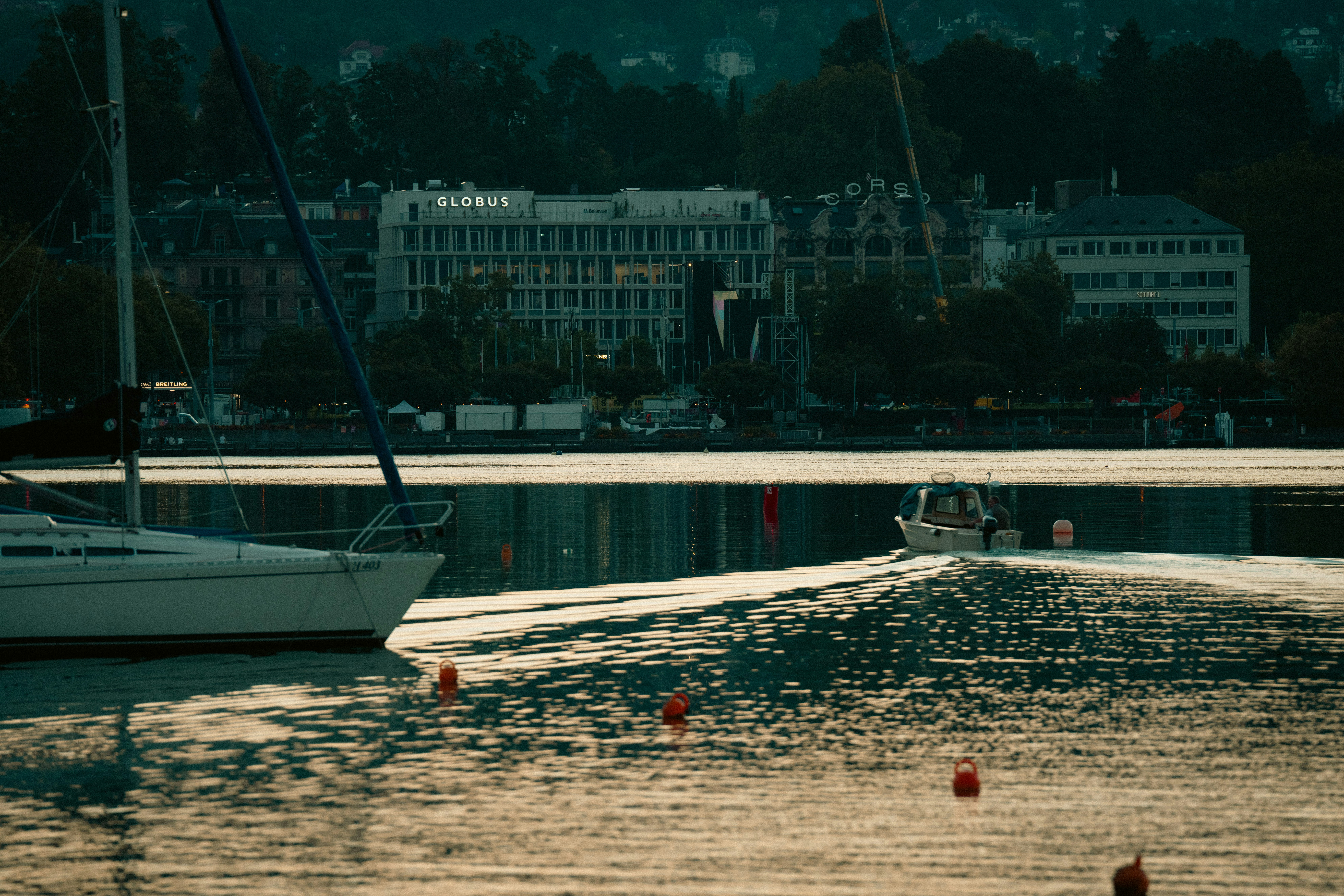 Boats on a calm lake with buildings in background