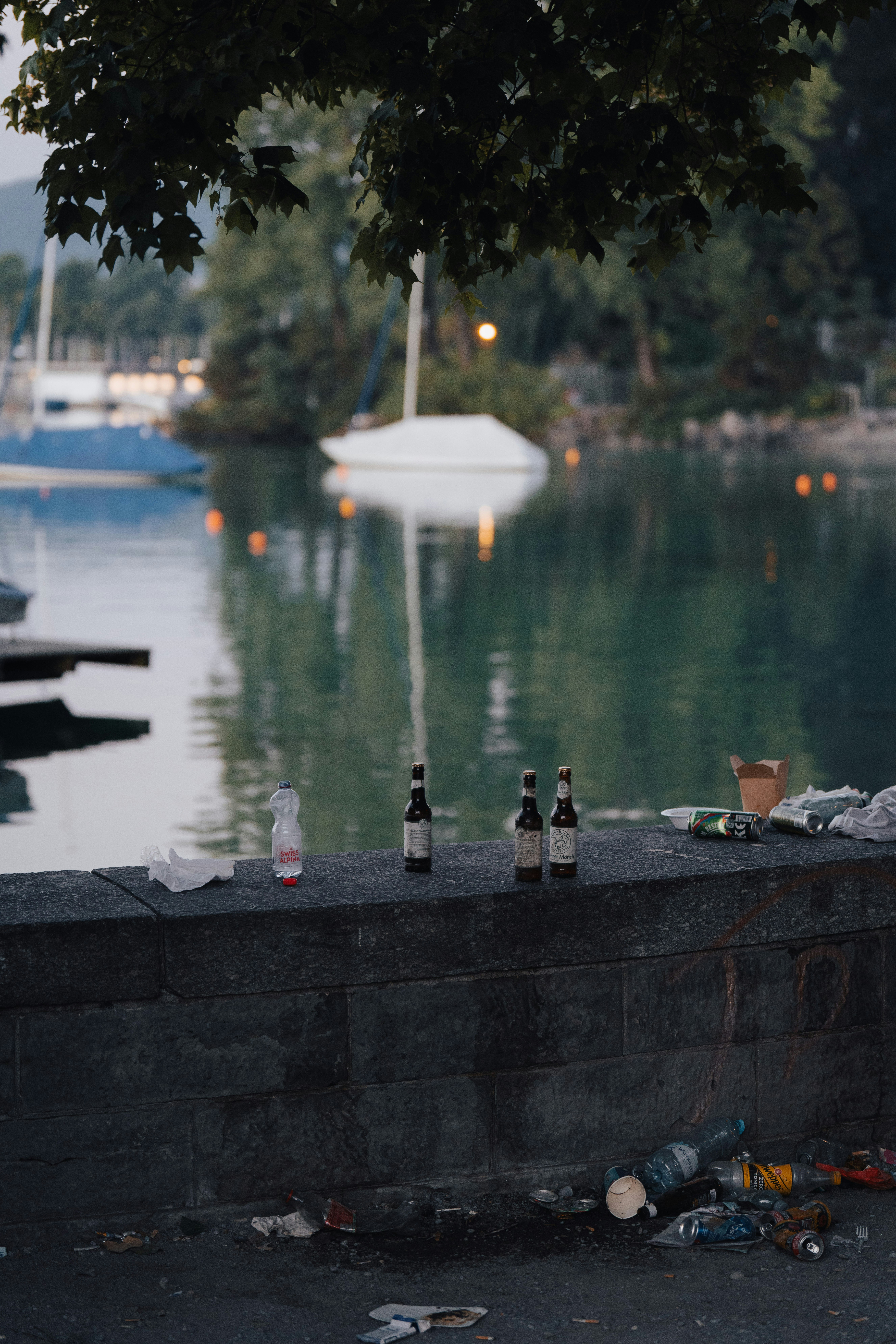 Bottles and trash on a wall by a lake