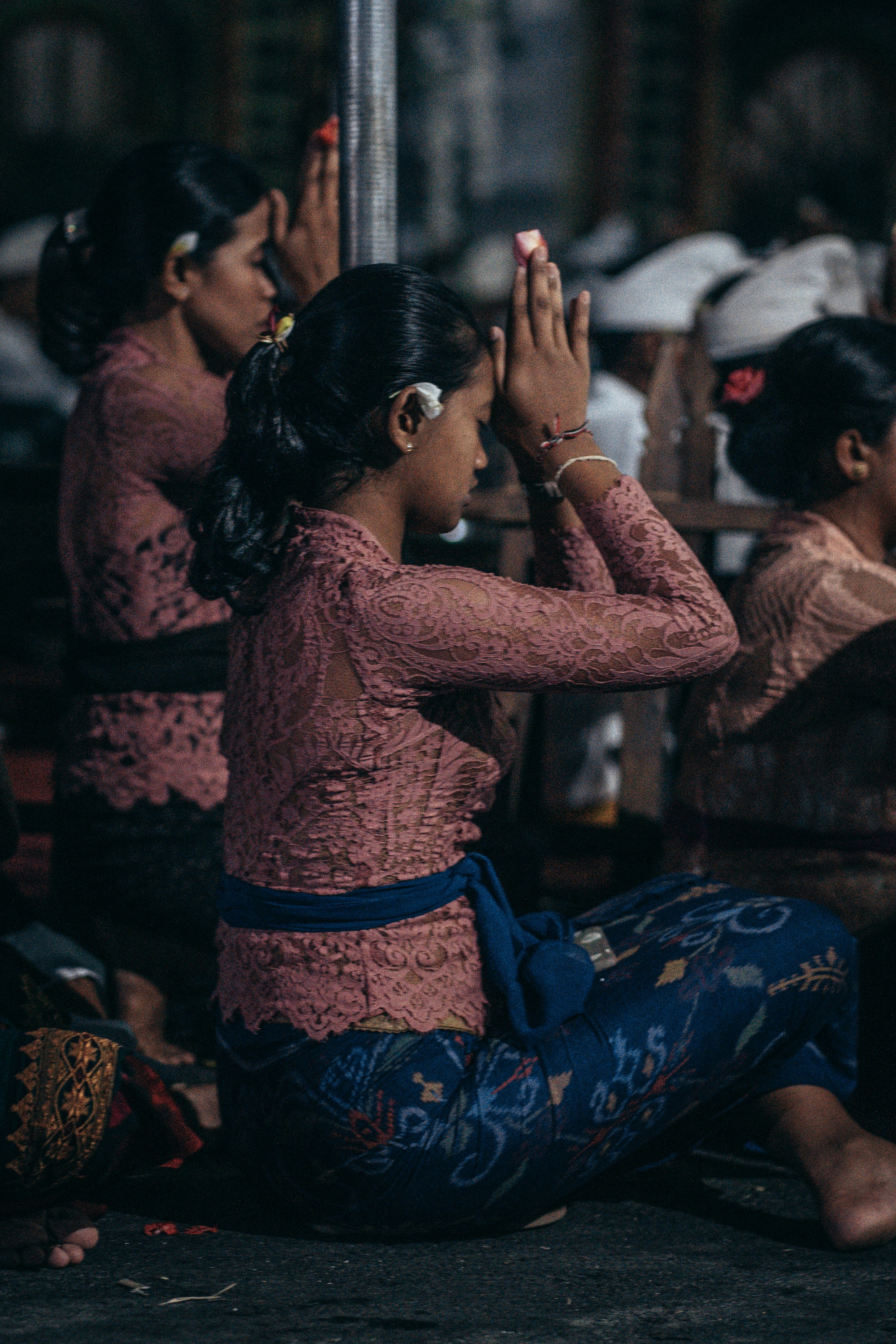Women in traditional clothing praying with hands together