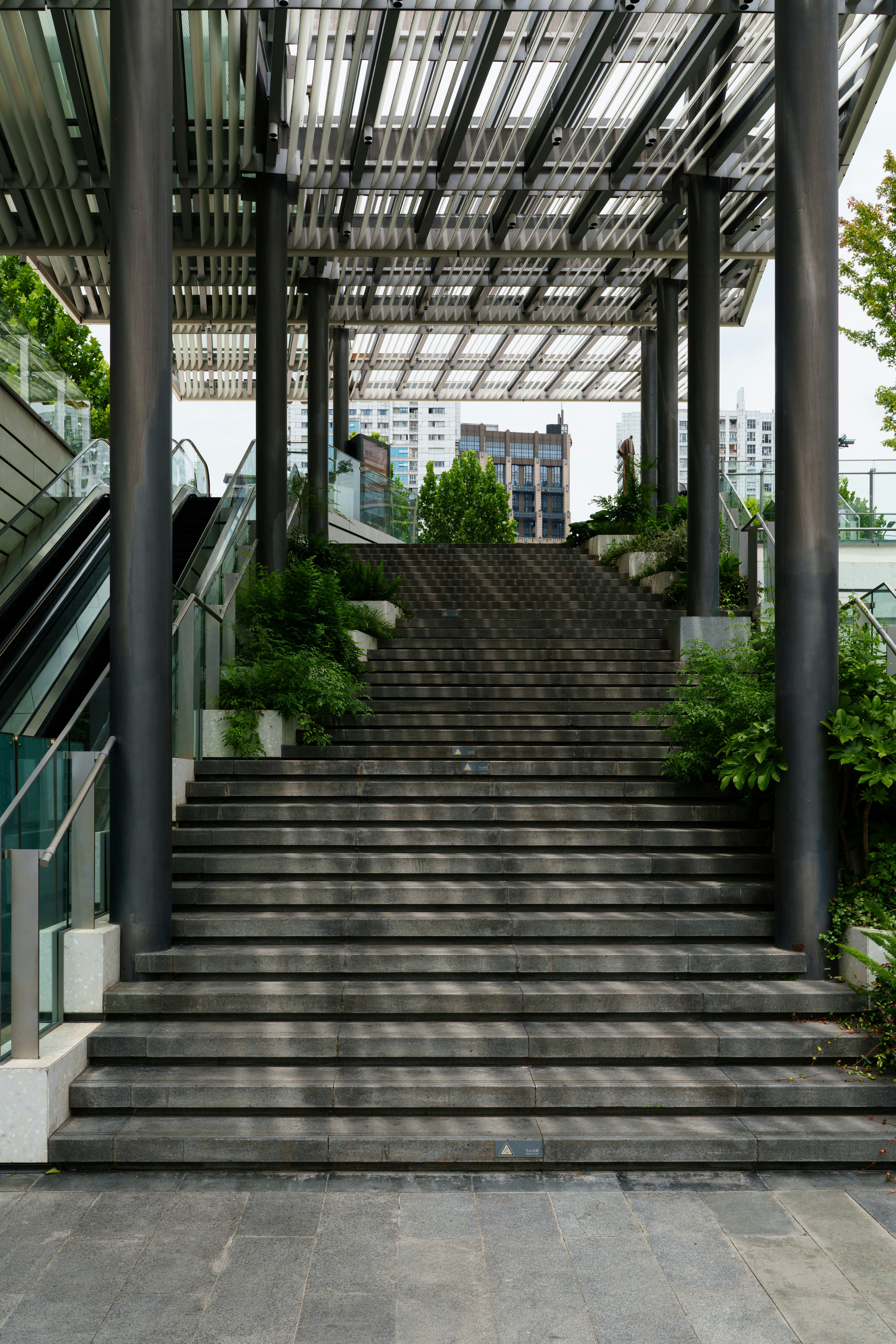 Modern outdoor stairway with escalators and greenery