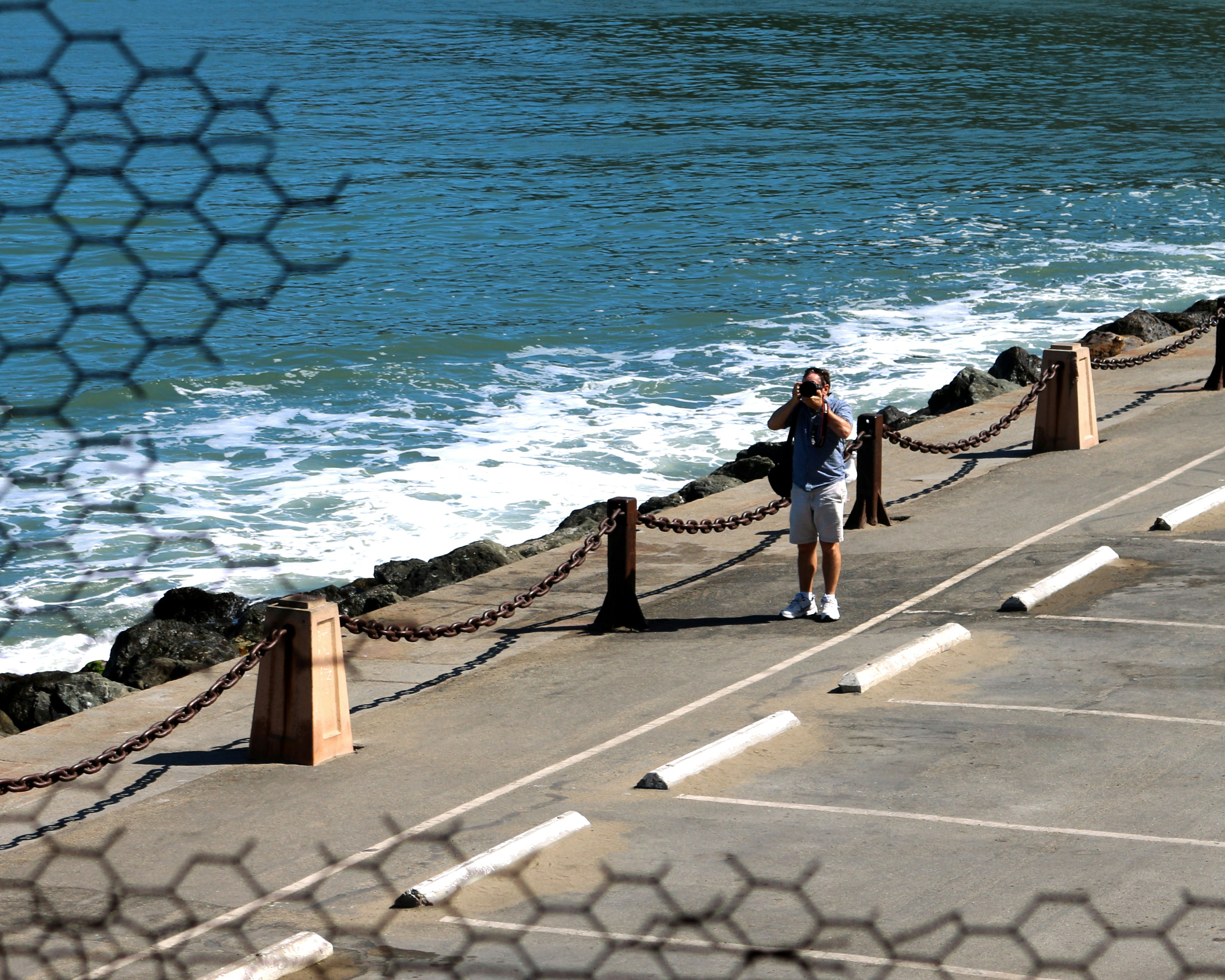 Person walking by the ocean waves on a sunny day.