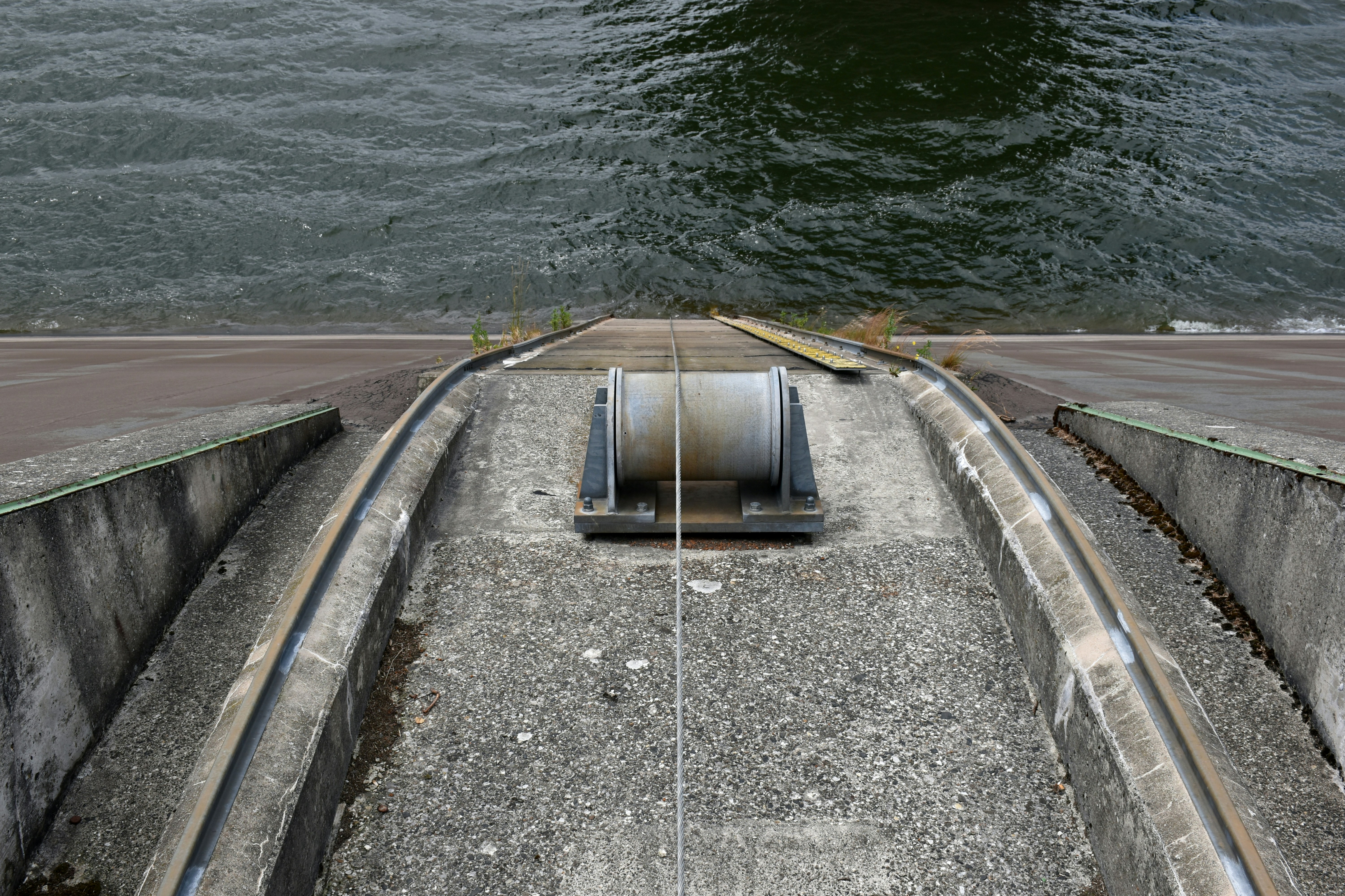 A detail of a dam (Germany - floodgate) | Water flows through a concrete channel towards the sea.