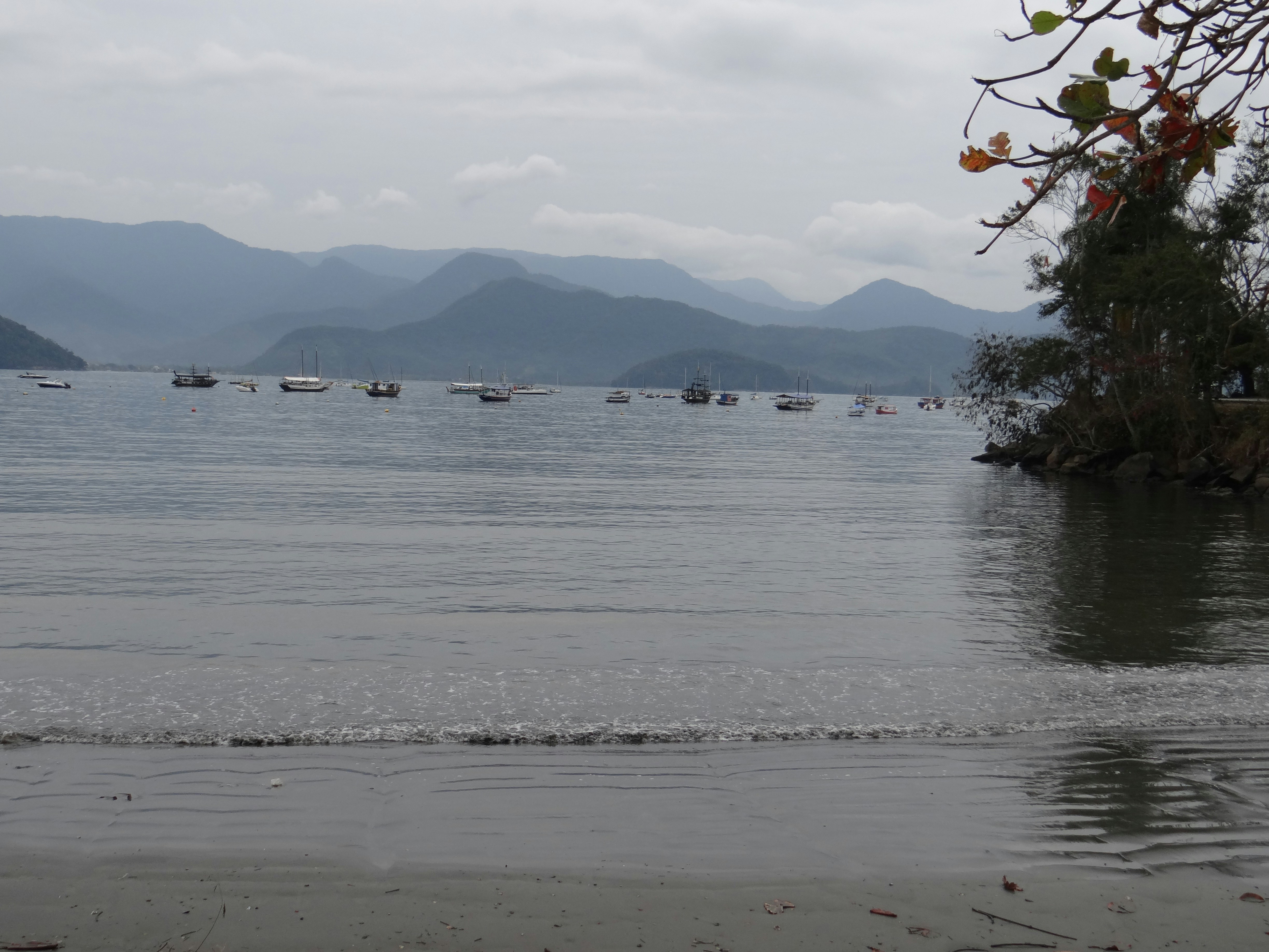 Calm lake with distant mountains under cloudy sky