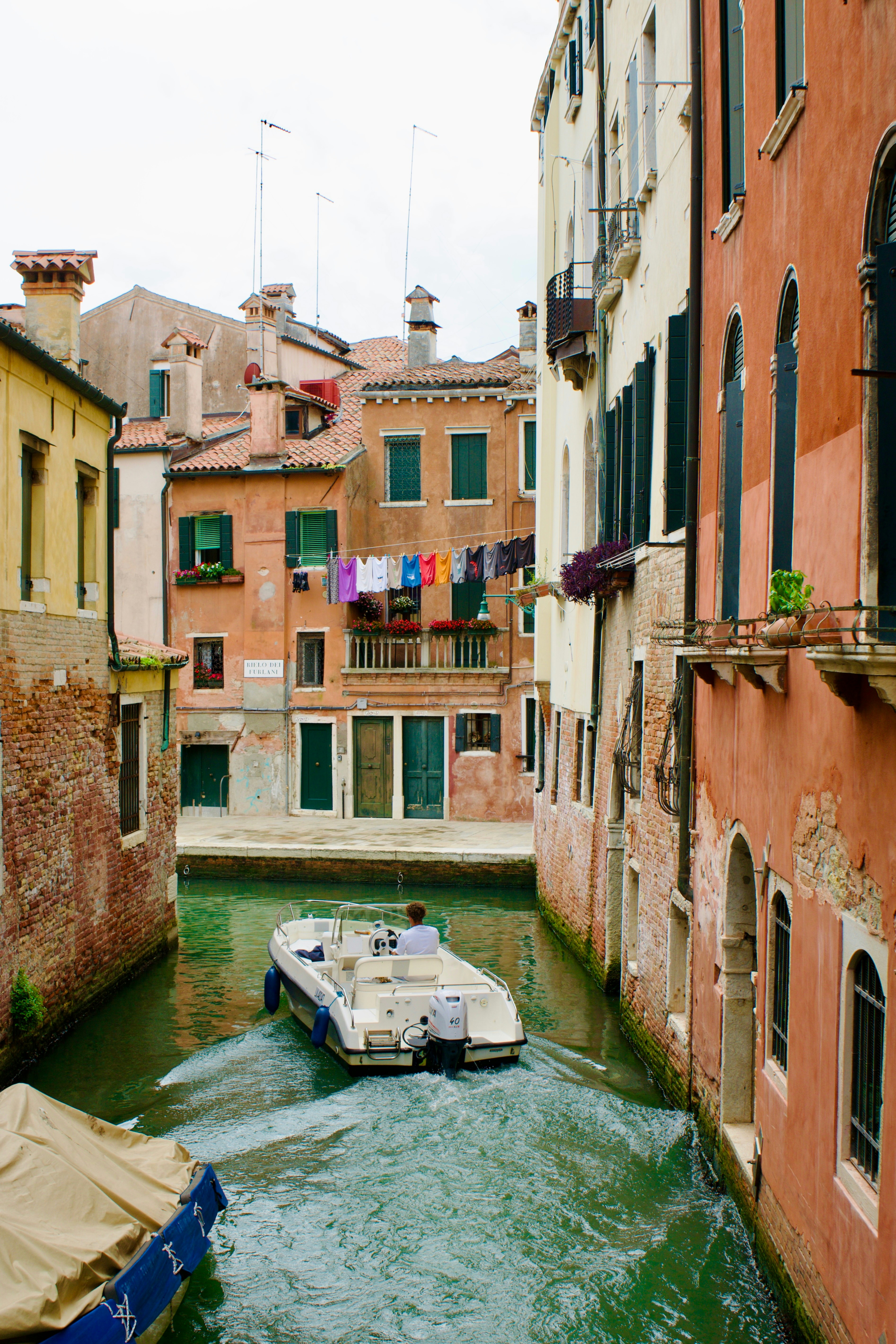 Boat in Venice | A boat navigates a narrow canal between colorful buildings.