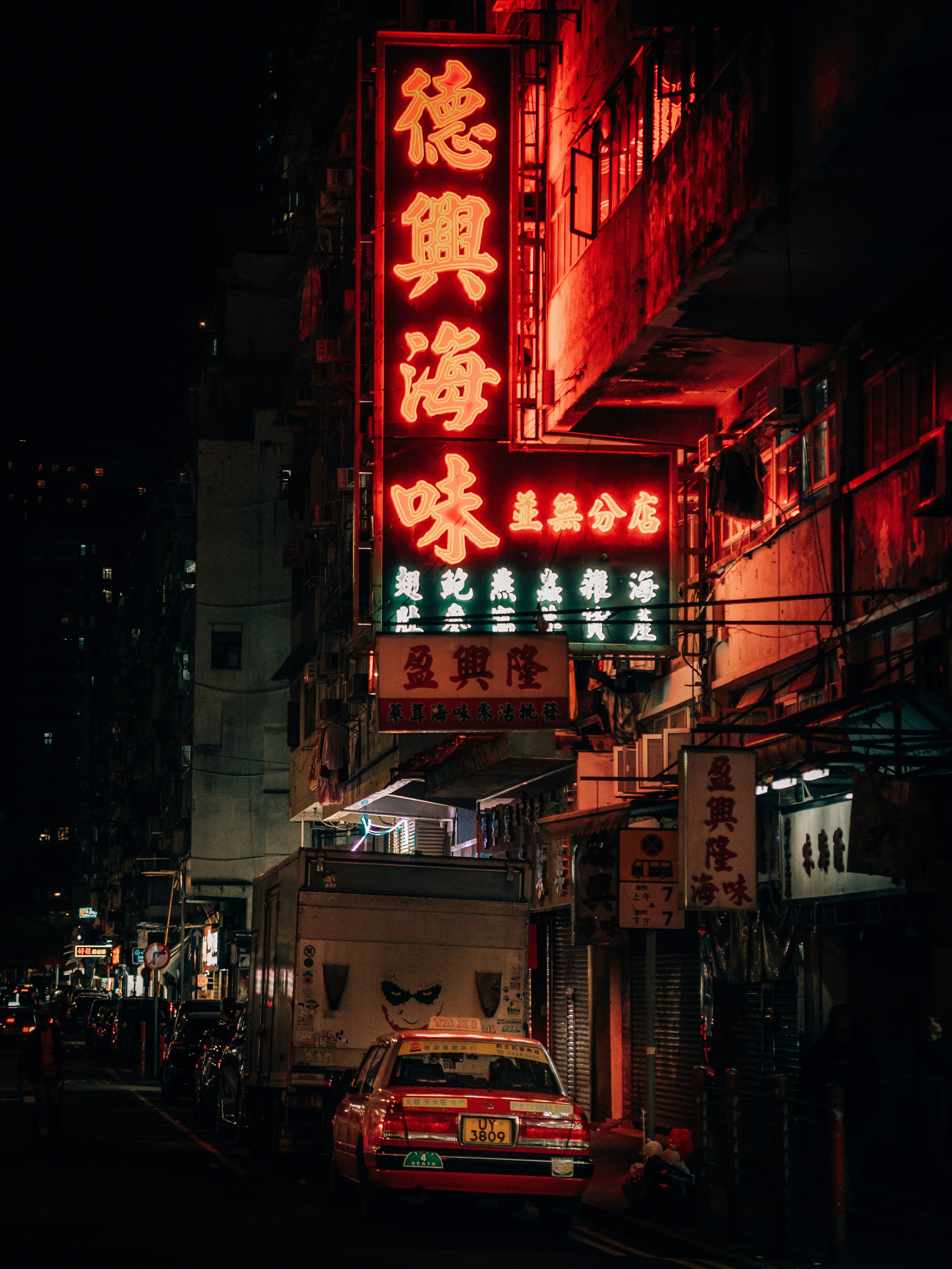 Neon signs illuminate a city street at night.
