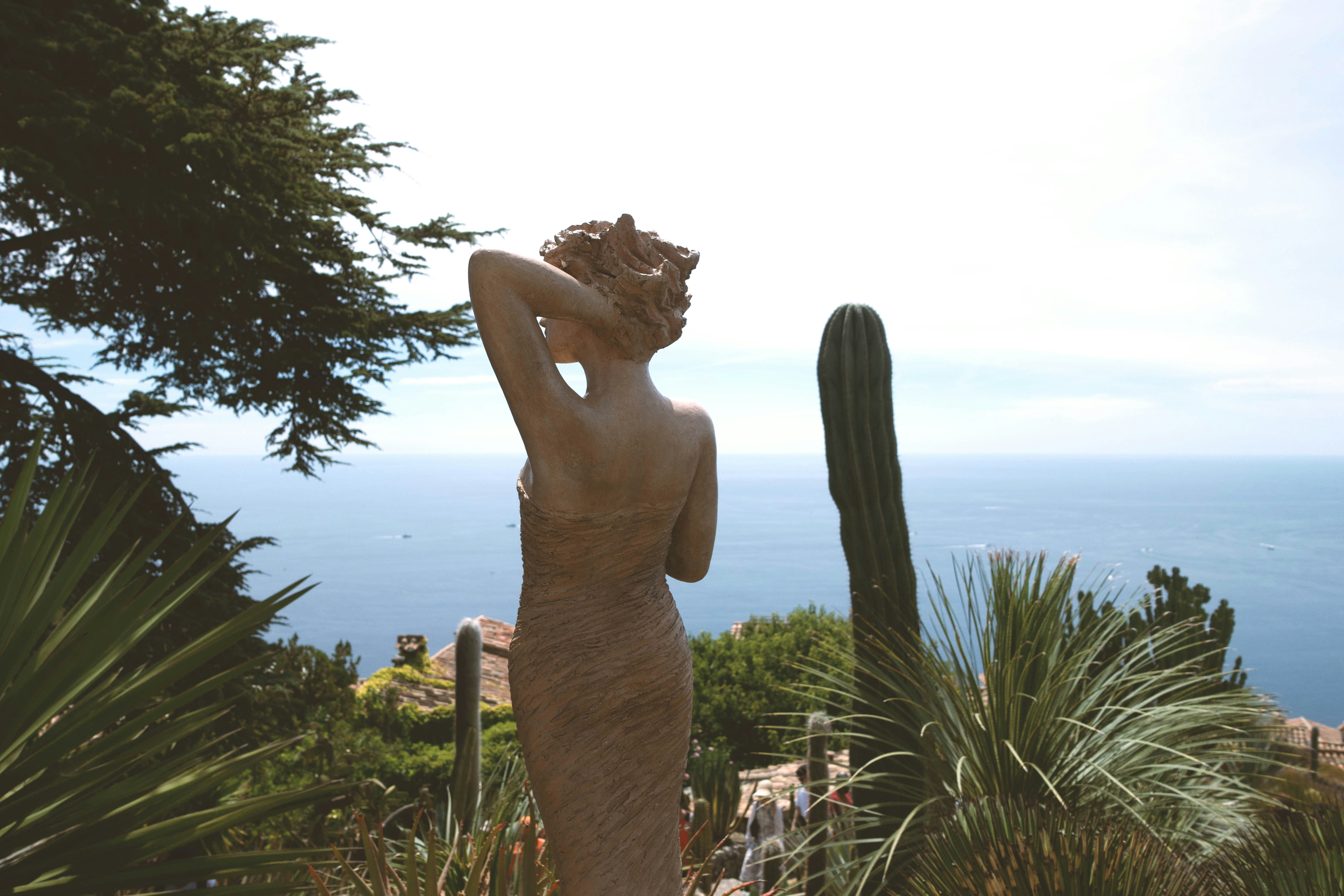 Statue of a woman with hands on head overlooking ocean