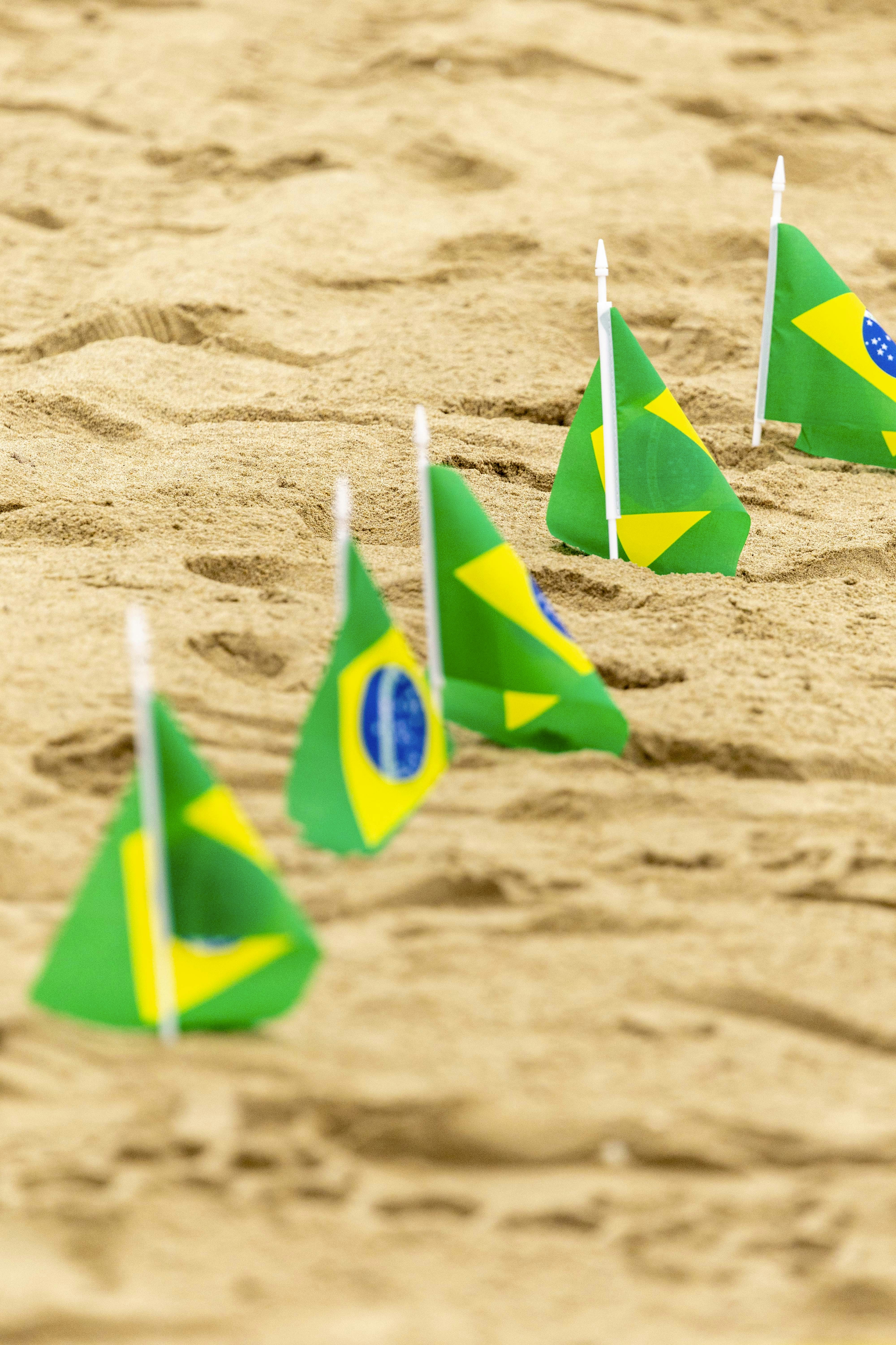 Several small brazilian flags planted in sand