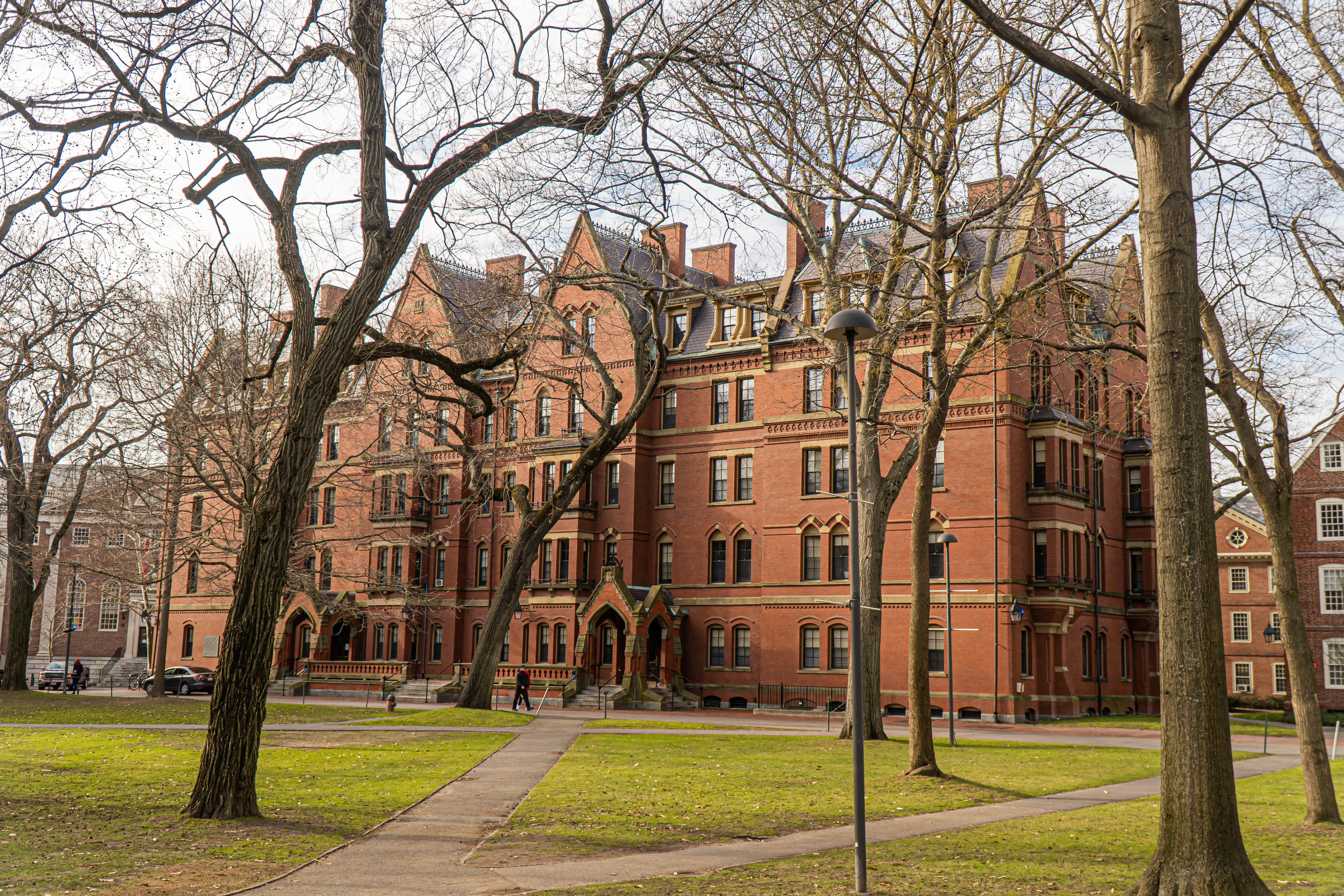 Historic brick building surrounded by bare trees and manicured lawns, reflecting a blend of architectural elegance and scholarly ambiance.