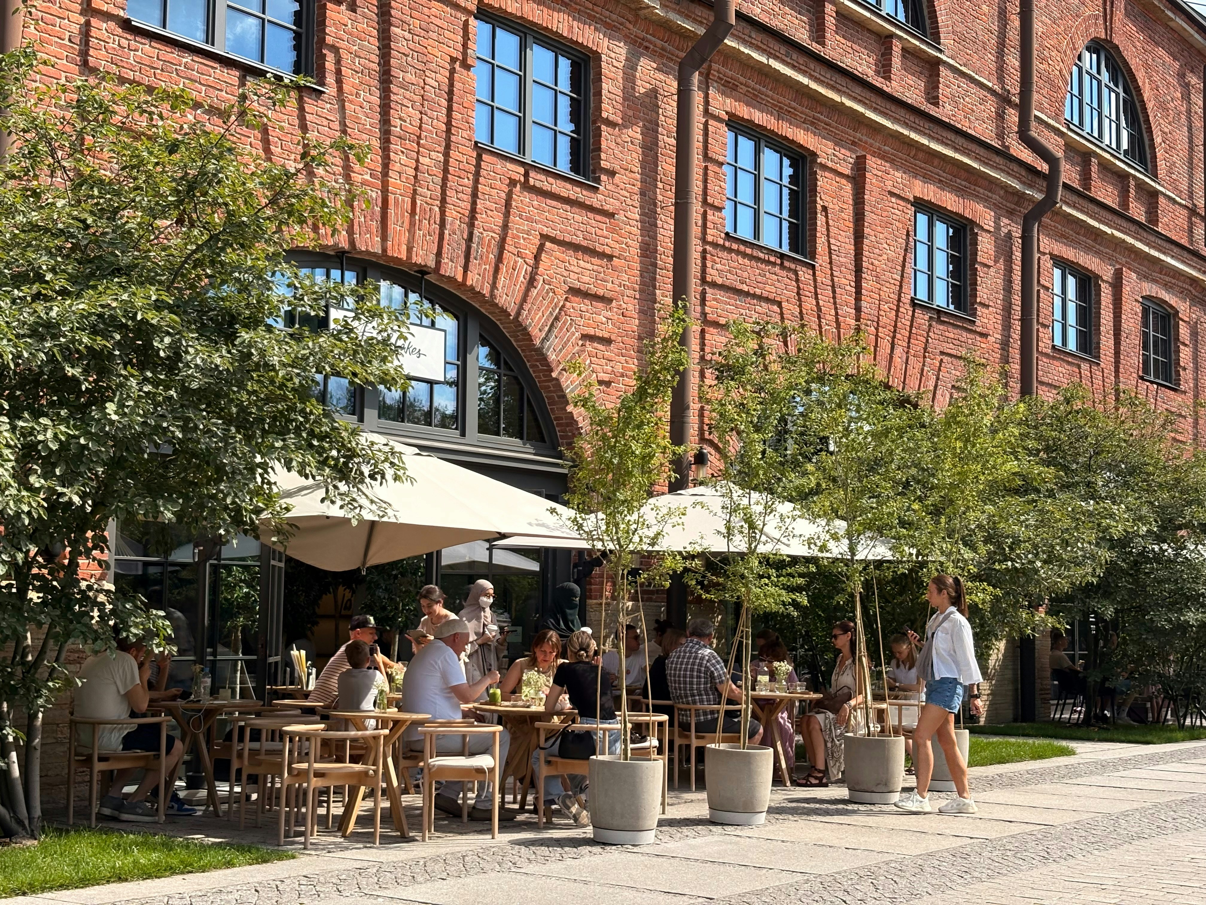People dining at an outdoor cafe under umbrellas.