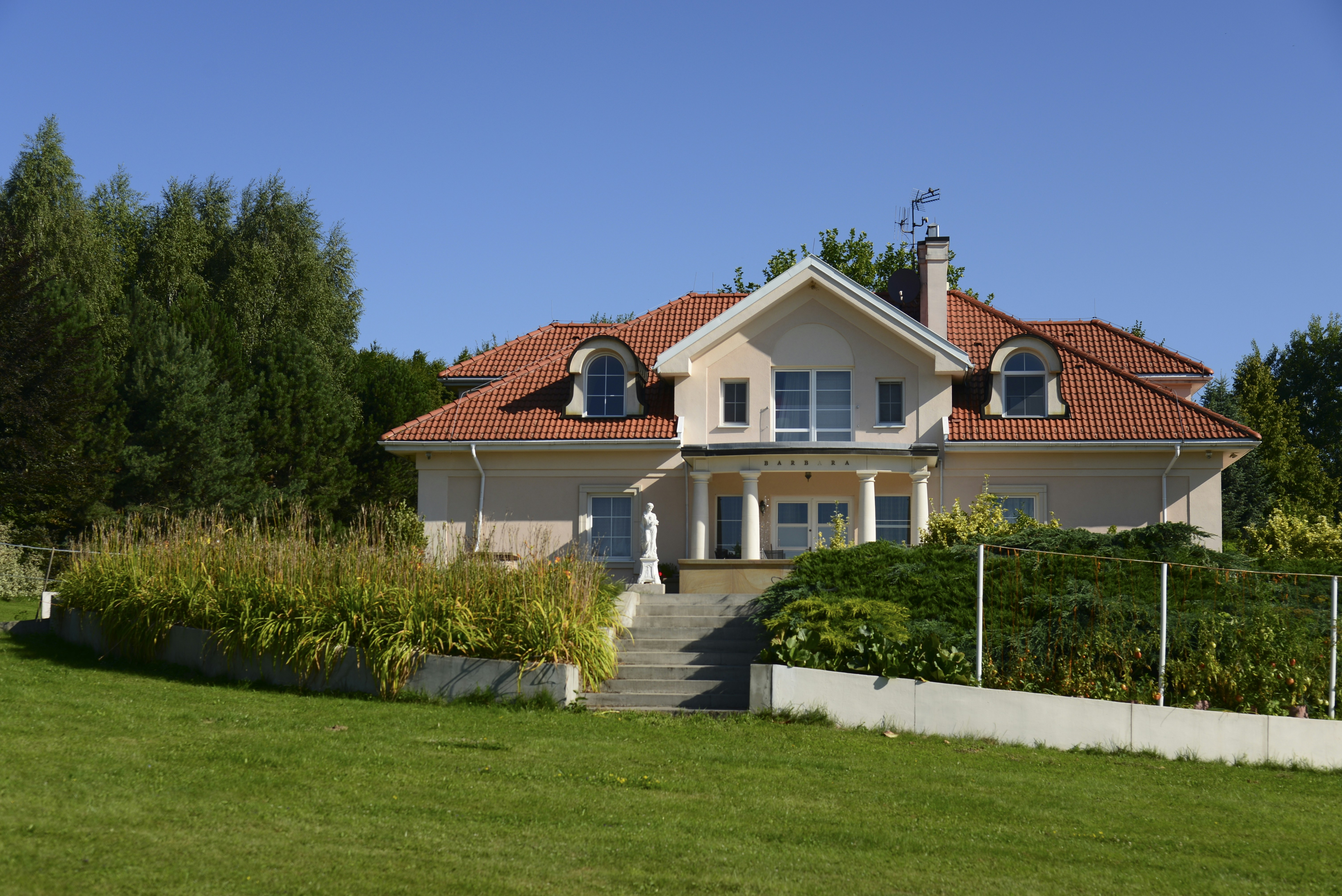 A large house with red roof and green lawn