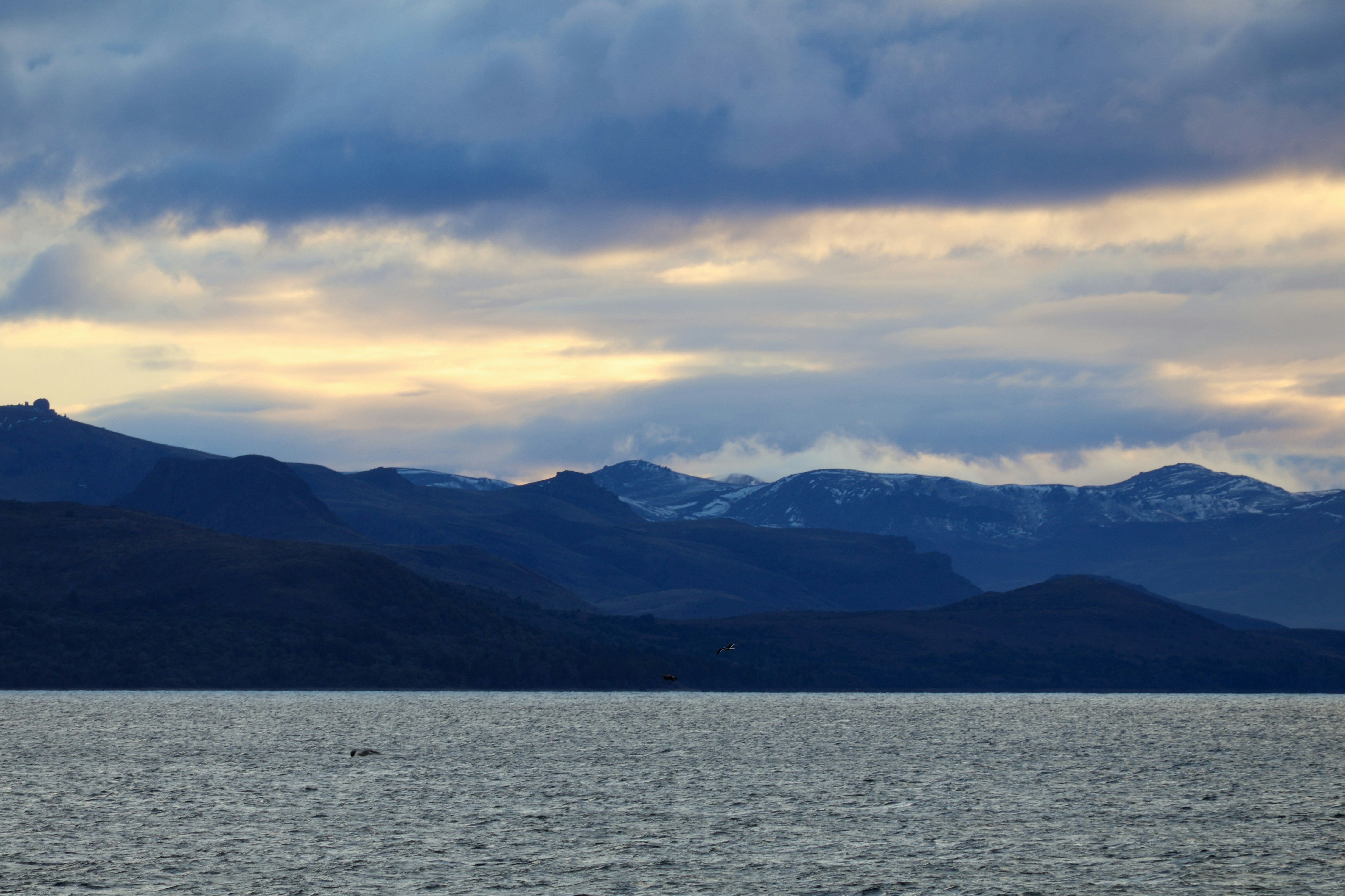 Dark mountains under a cloudy sky at dusk.