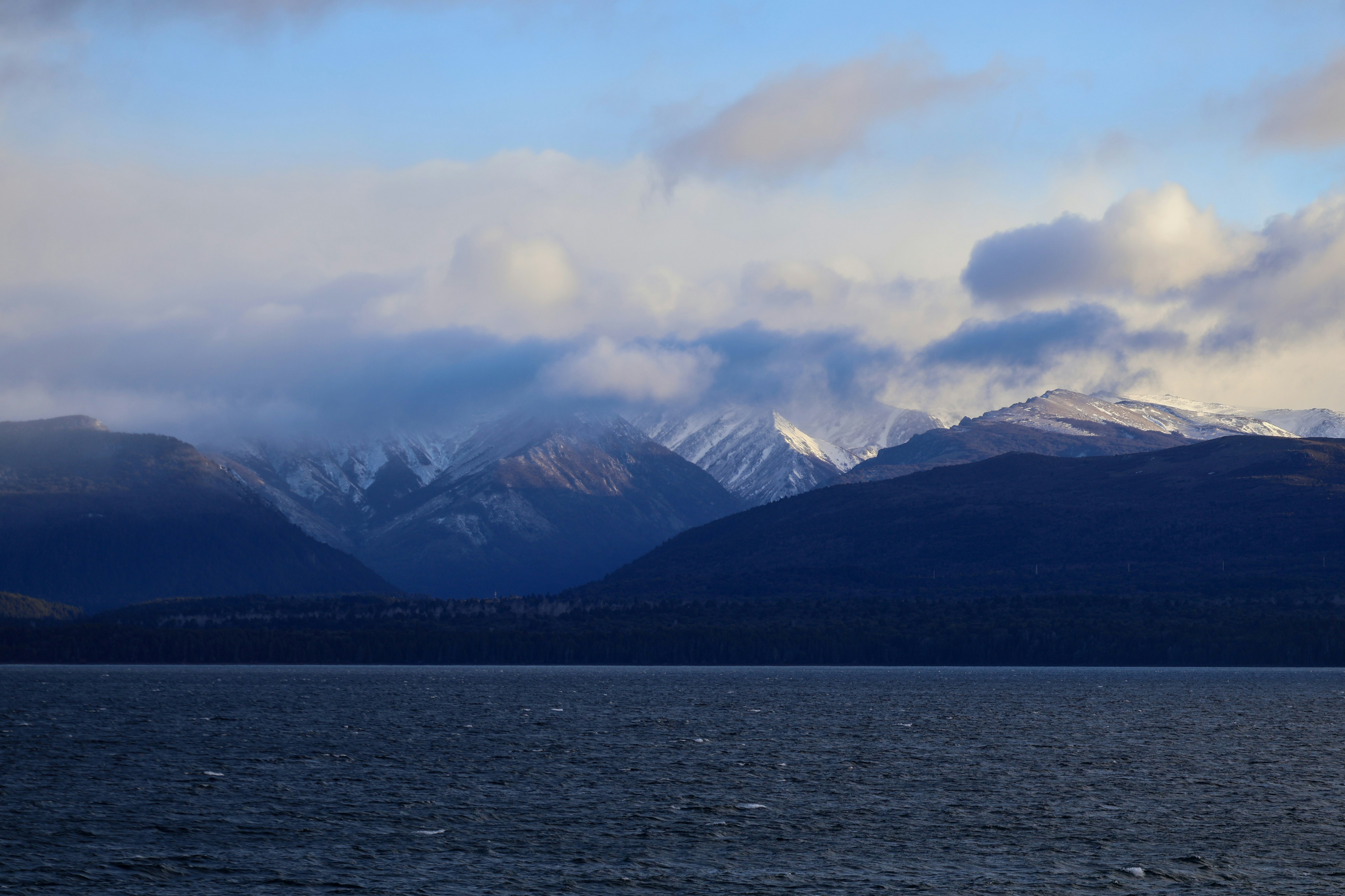 Snow-capped mountains shrouded in mist over calm water